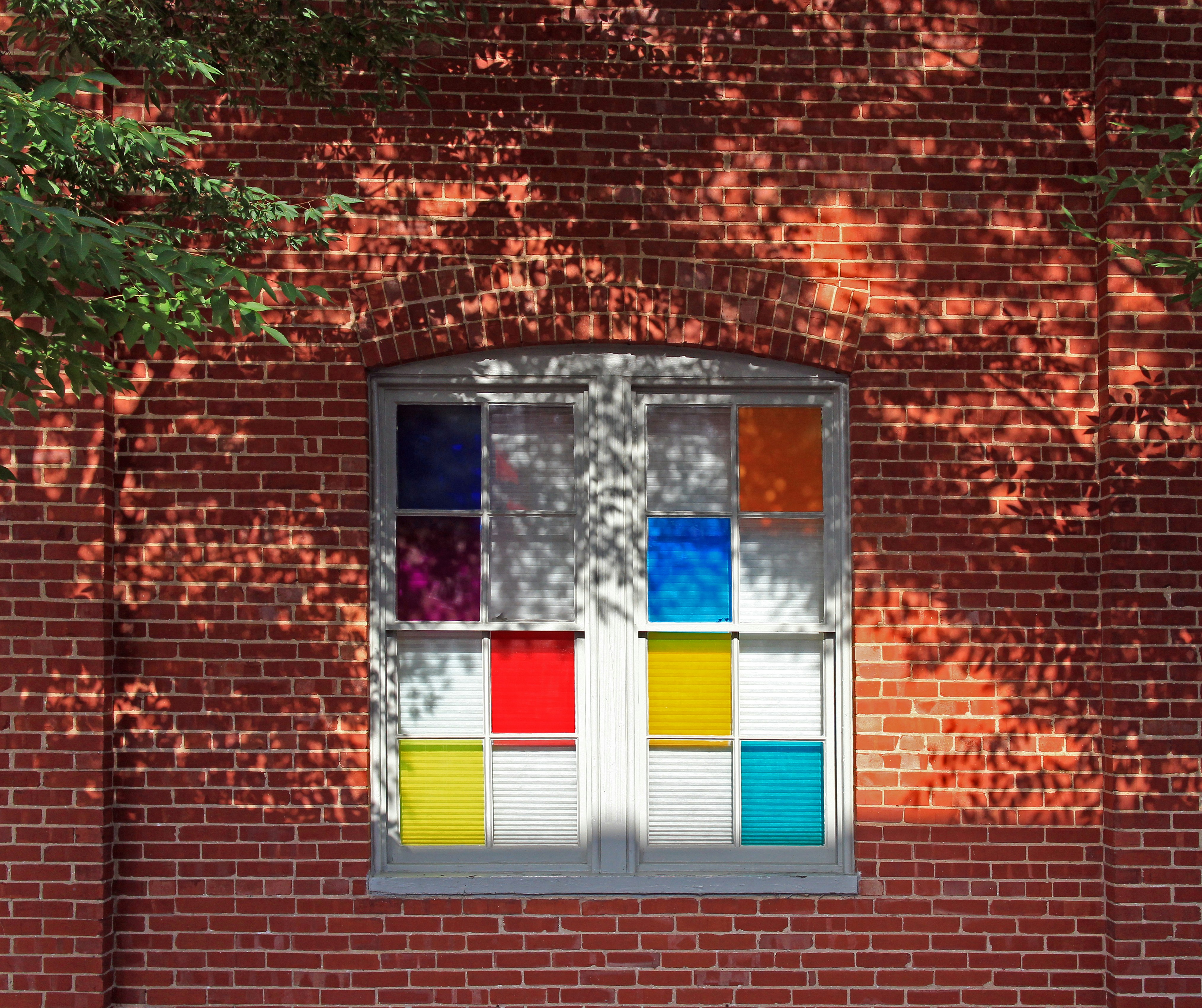 Patchwork Window on a Sunlit Brick Facade