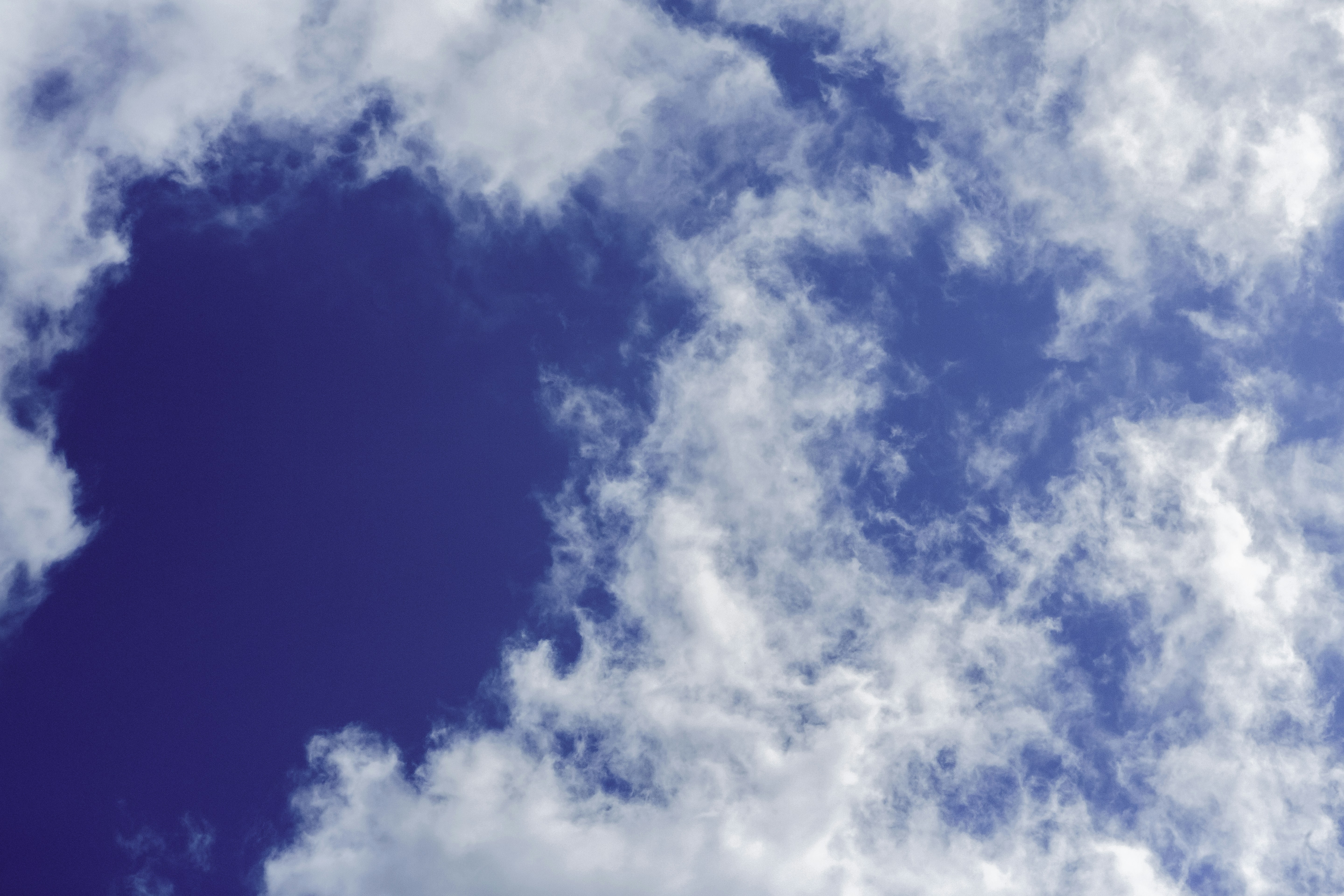 Bright blue sky with scattered white fluffy clouds creating soft shapes. Clear daytime sky with natural cloud formations. Atmospheric weather background with a peaceful sky. | Blue sky with white, fluffy clouds.