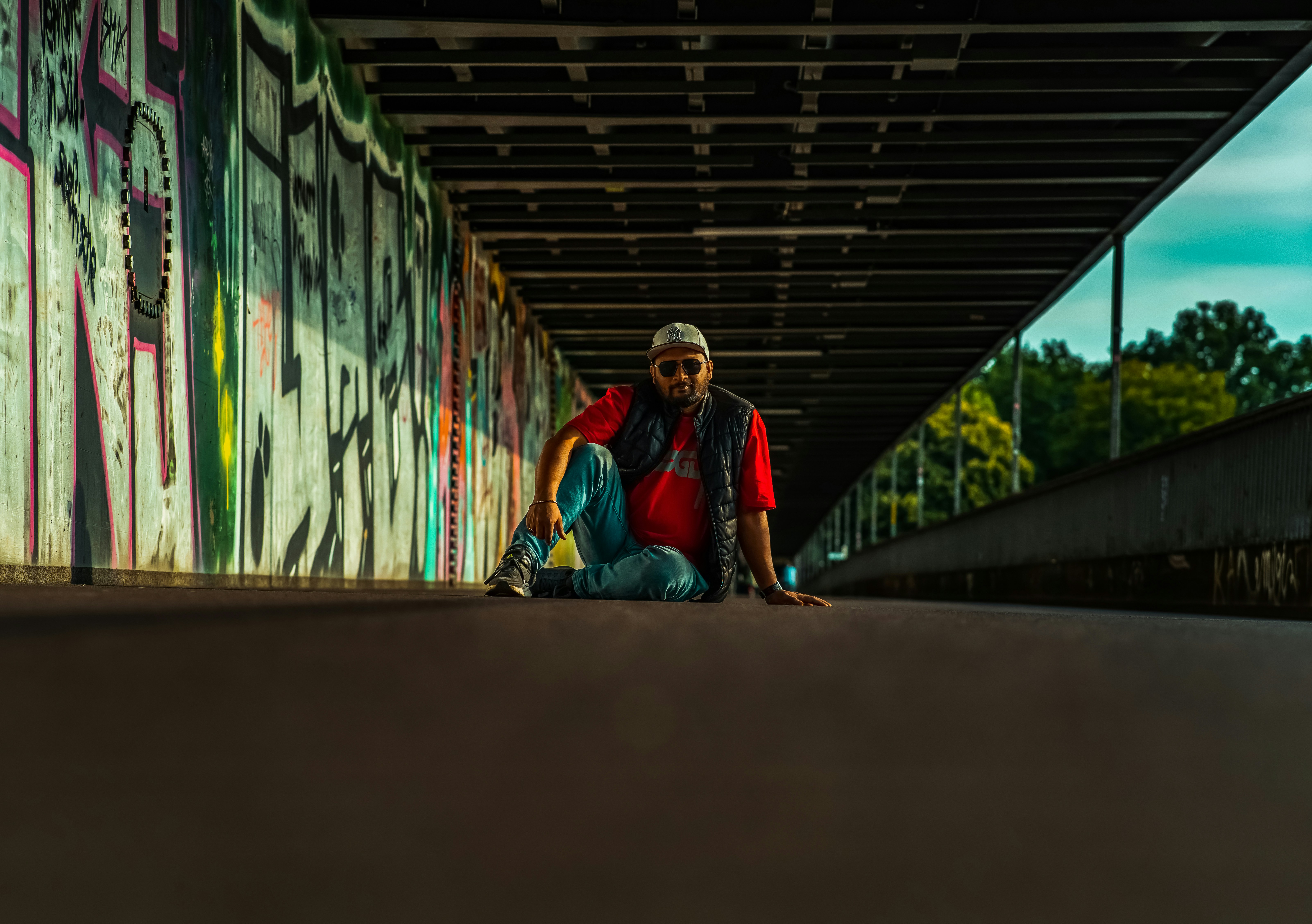 Man sits in a graffiti-covered tunnel.