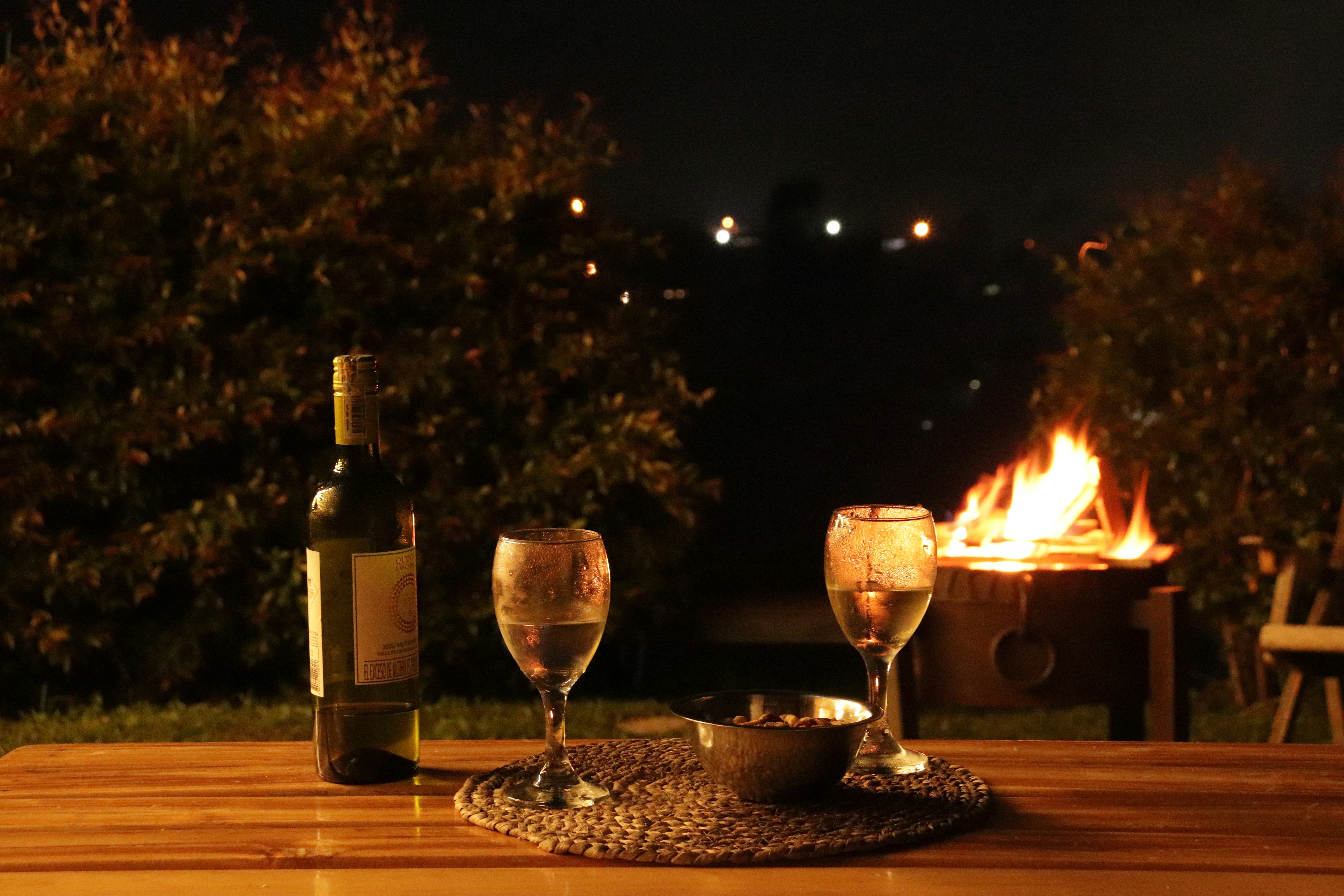 Wine and fire create a romantic, outdoor atmosphere.