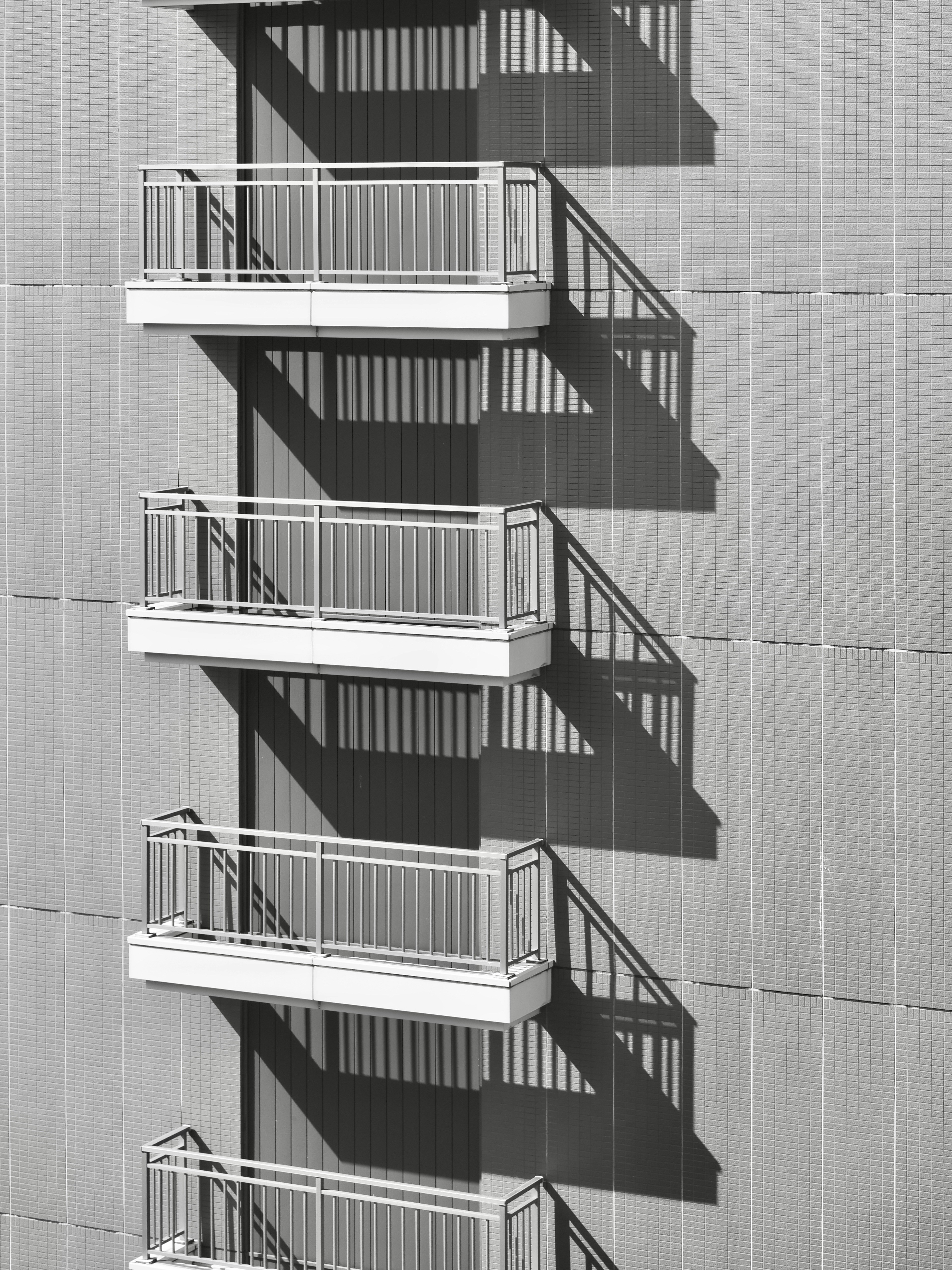 Balconies casting intricate shadows on a textured wall, showcasing architectural lines and patterns.