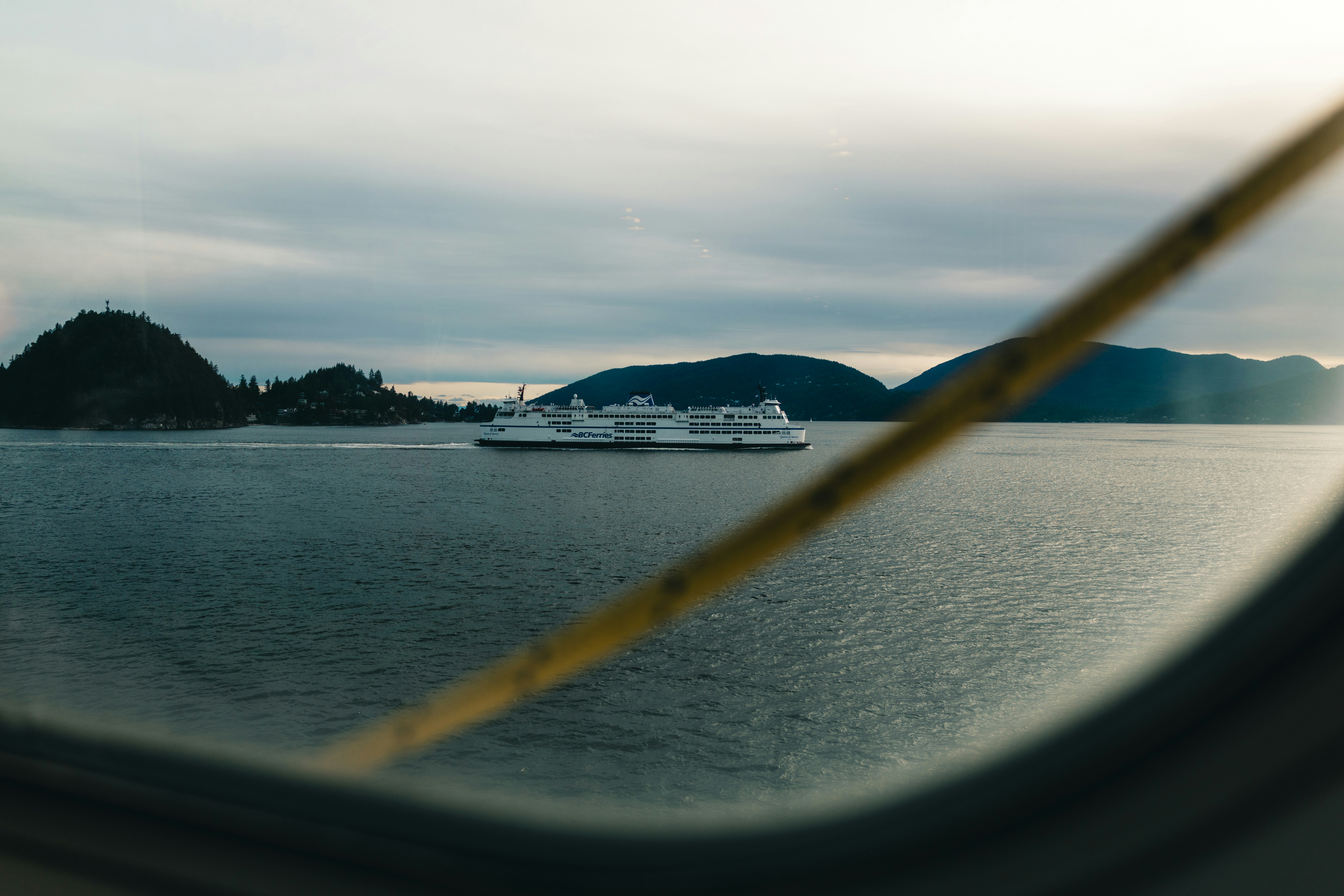 Ferry navigating through calm waters, framed by distant mountains and a cloudy sky. The scene captures a tranquil maritime moment.