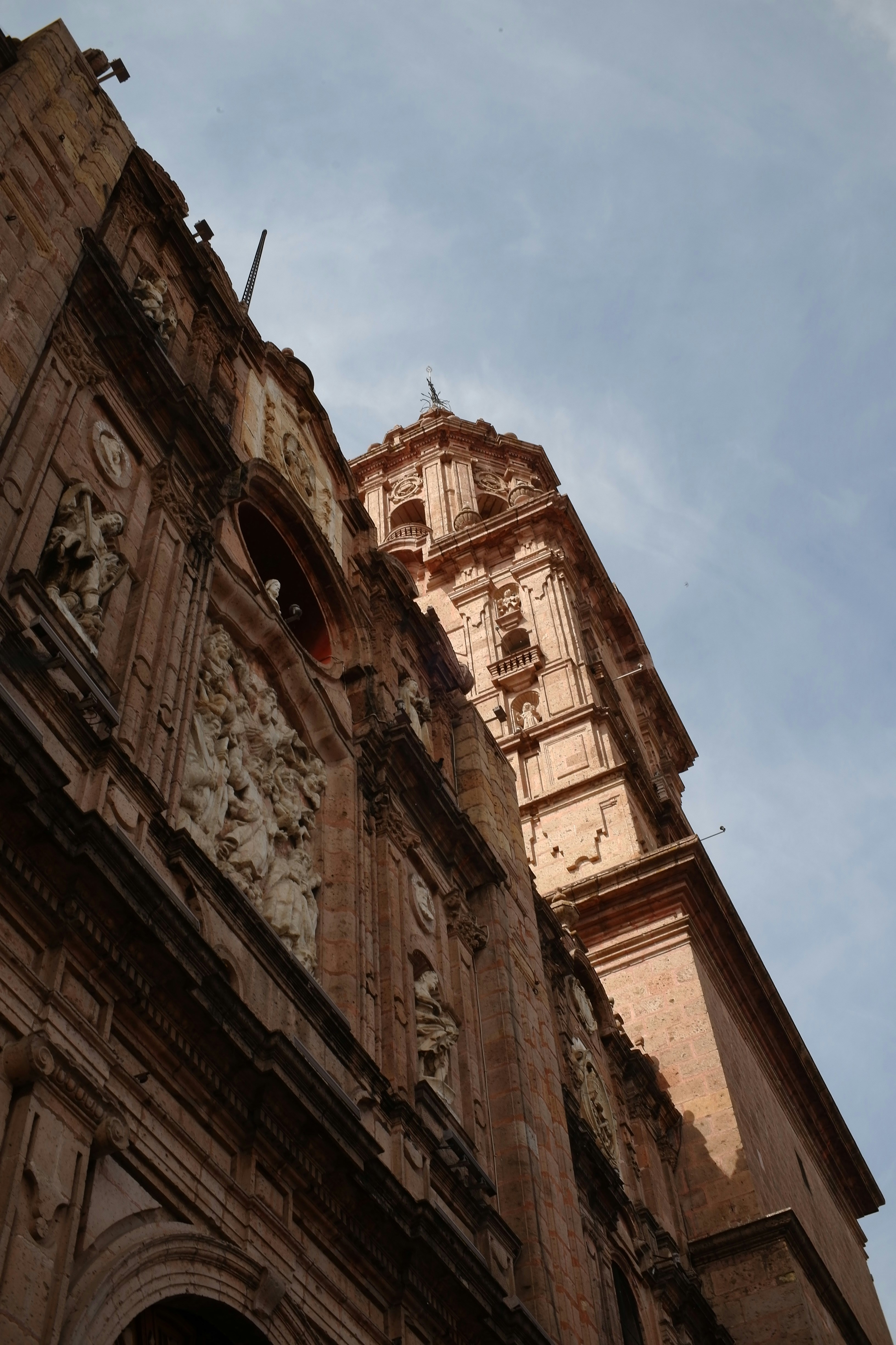 An ornate building rises against the cloudy sky.