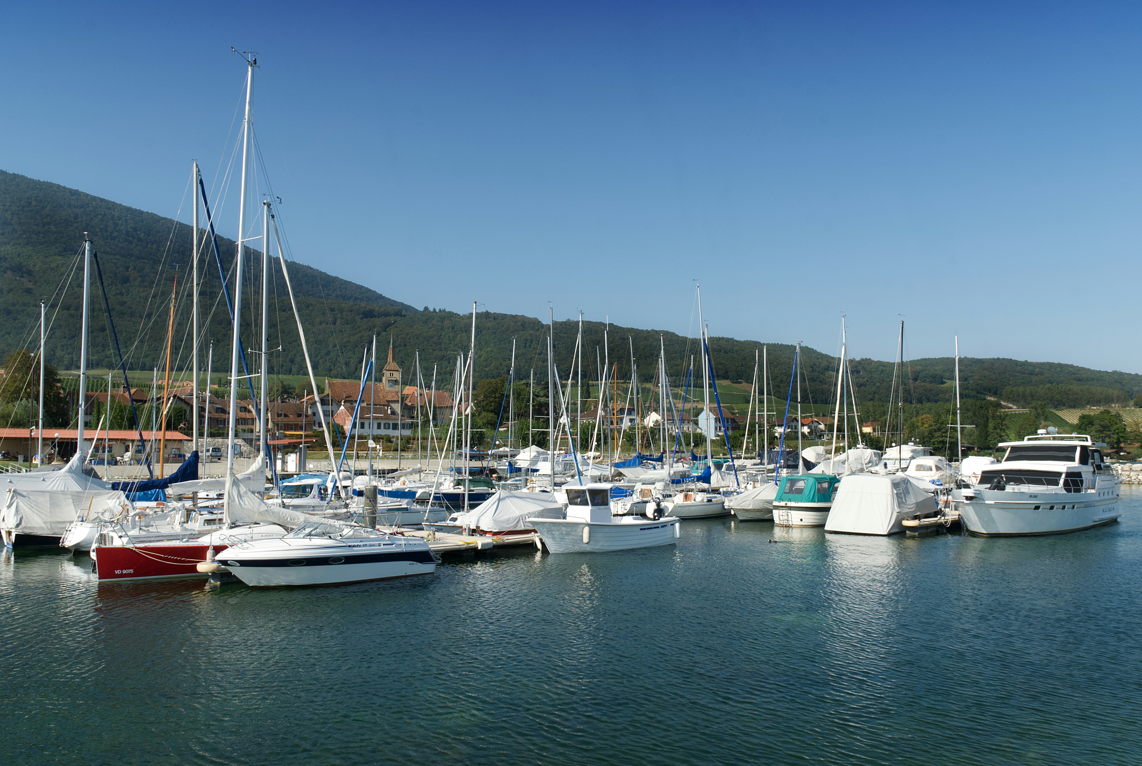 Ship harbor on Lake Neuchâtel | Sailboats are docked in a marina on a sunny day.