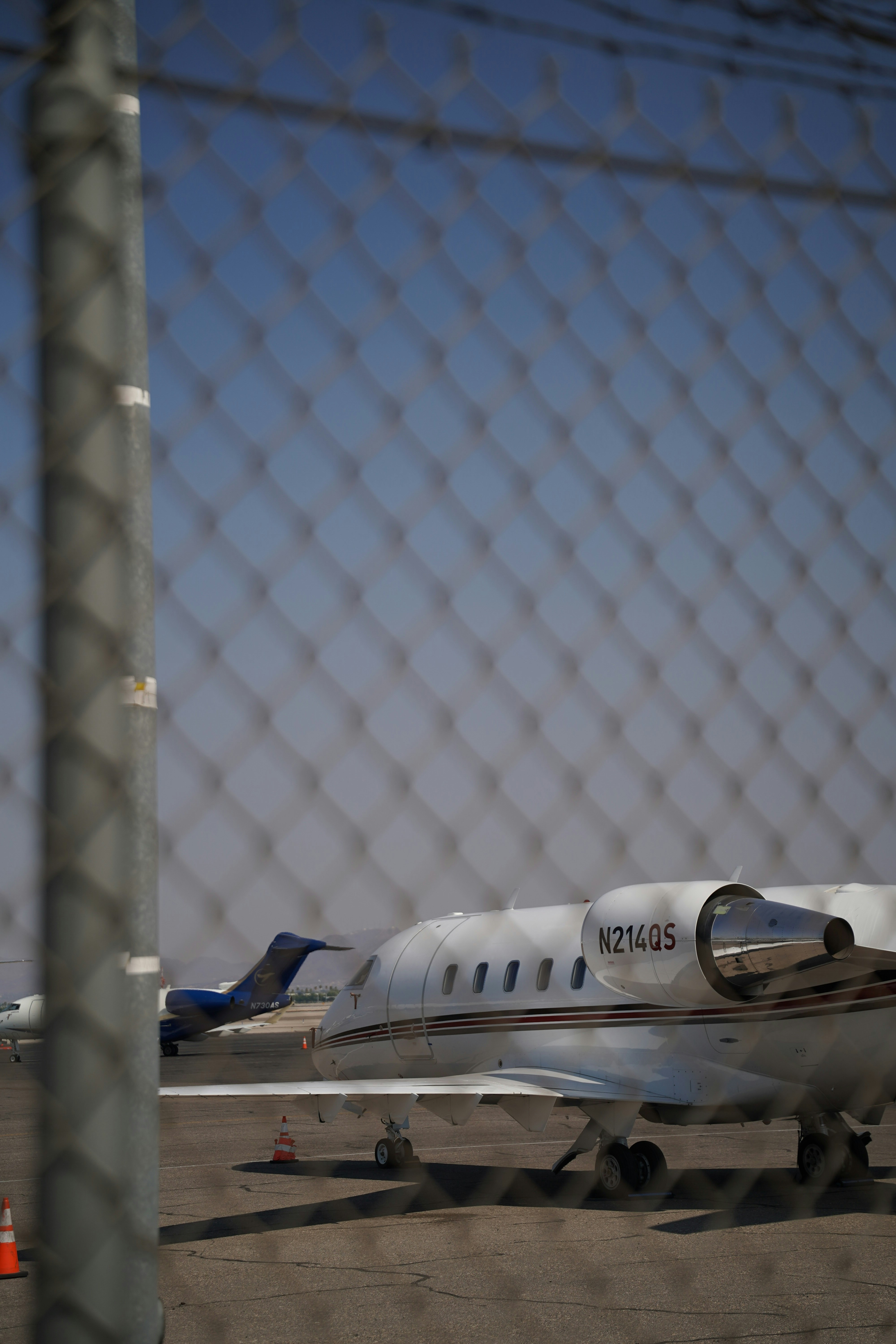 Private jets sit behind a chain-link fence.