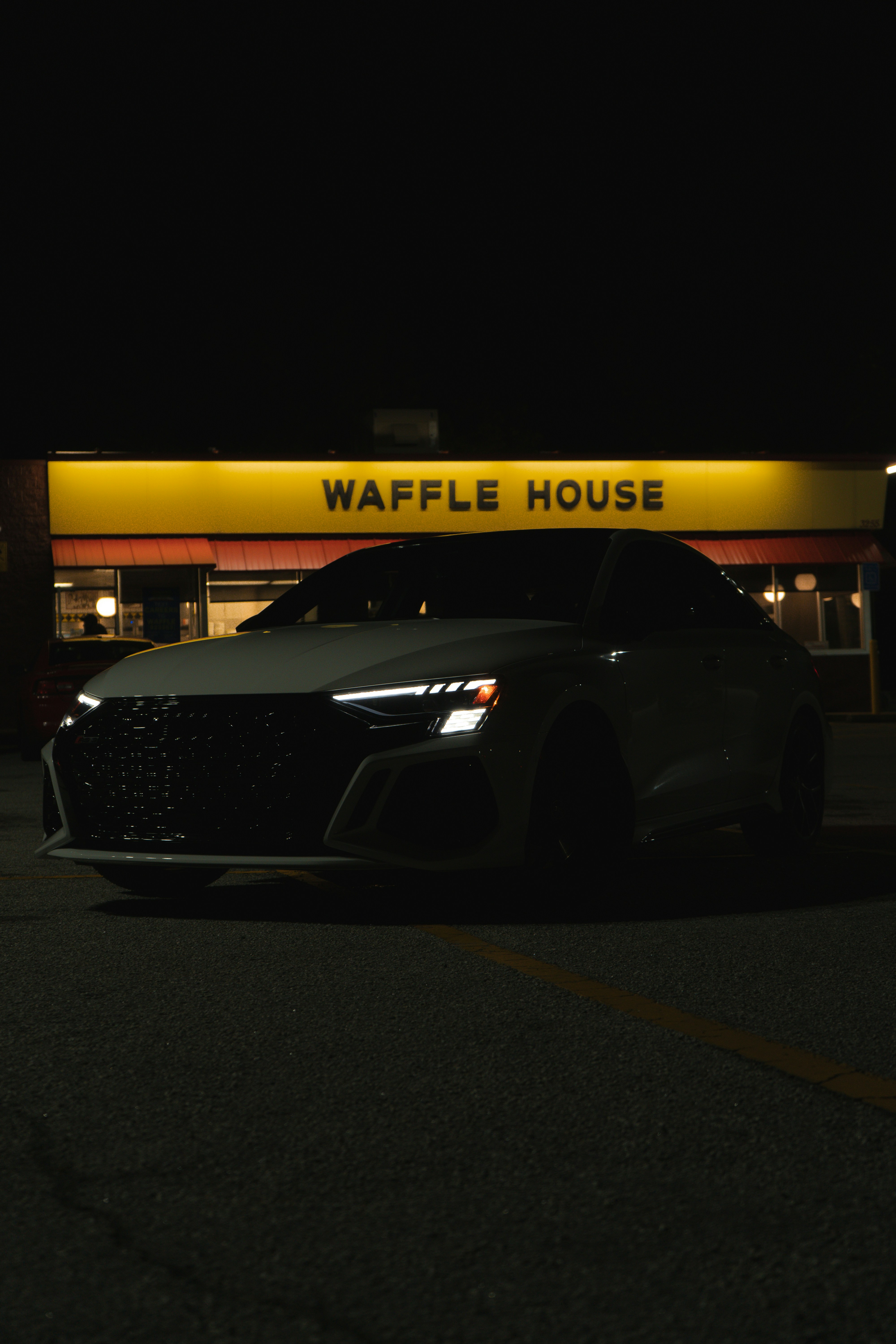 A car sits outside of a waffle house.
