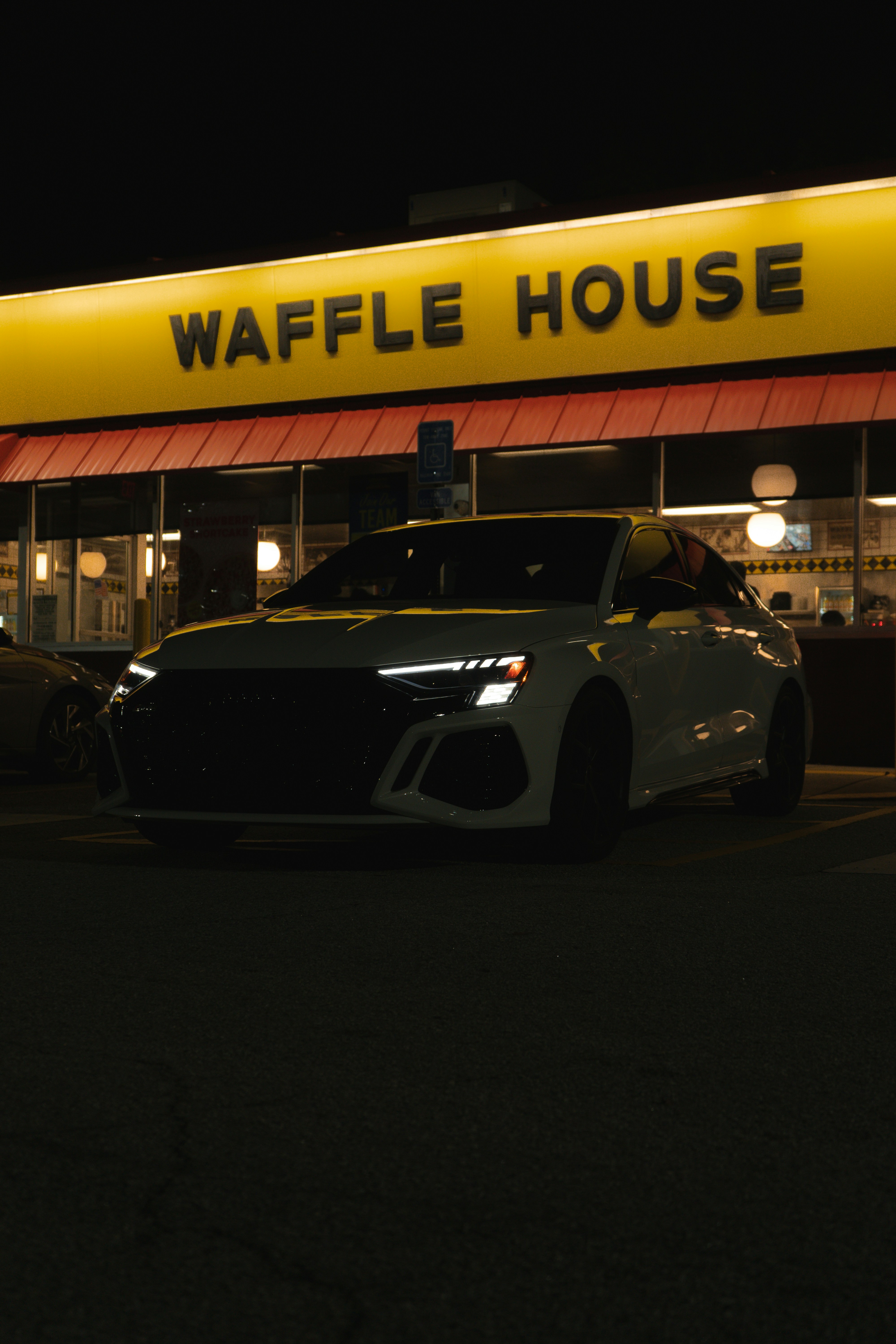 A white audi car parks in front of waffle house.