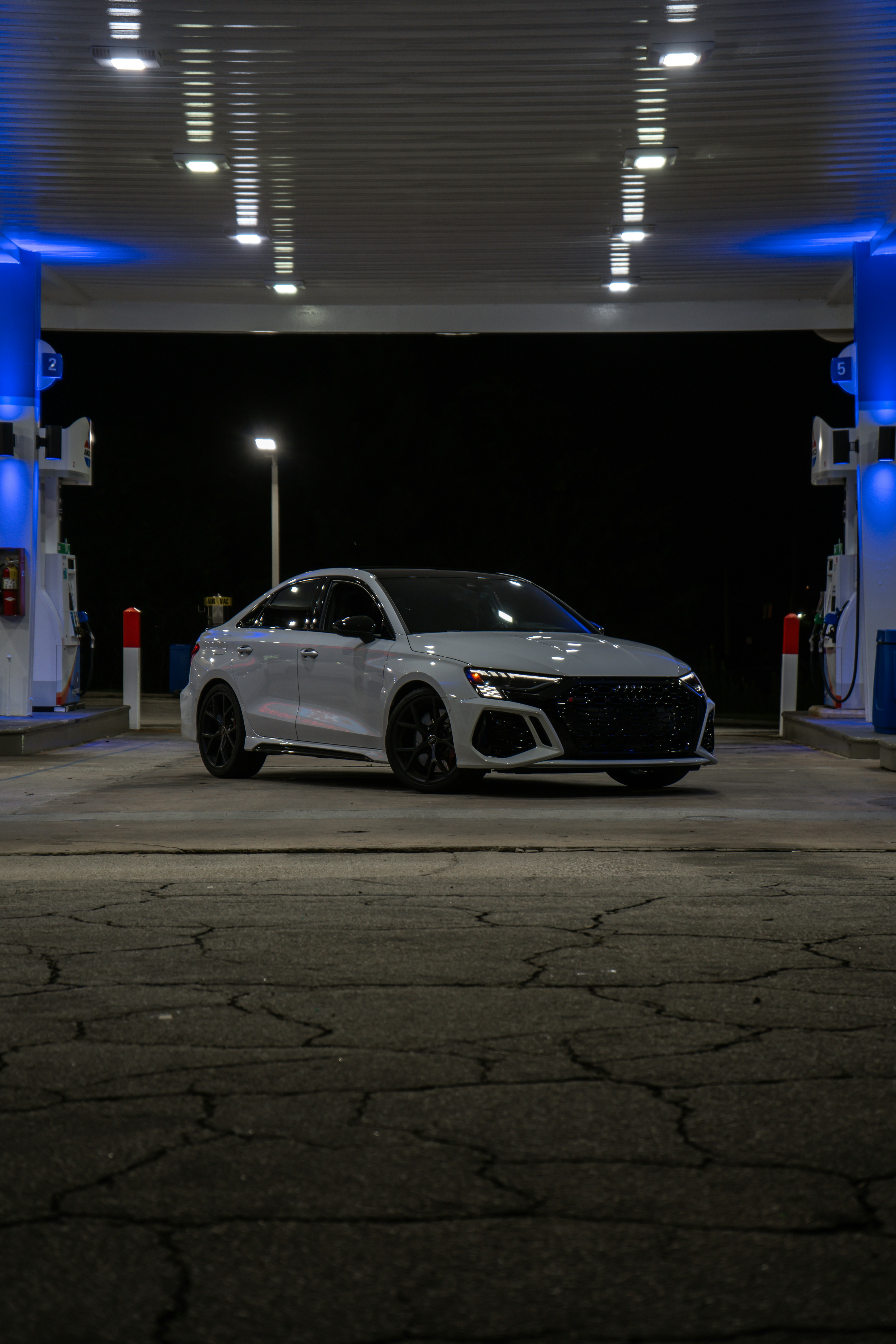 A gray car parked at a gas station.