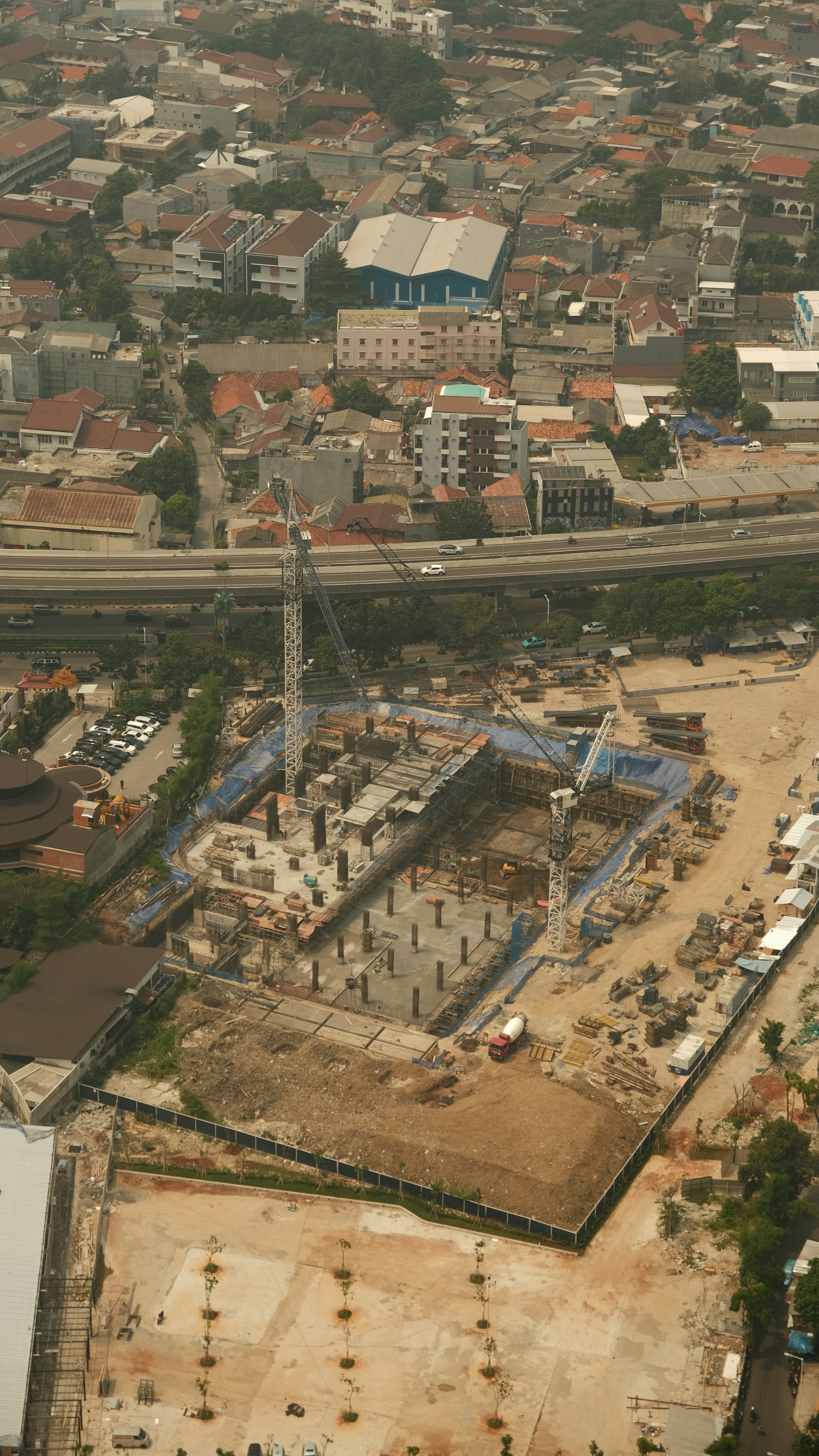 Construction site with cranes and buildings nearby.