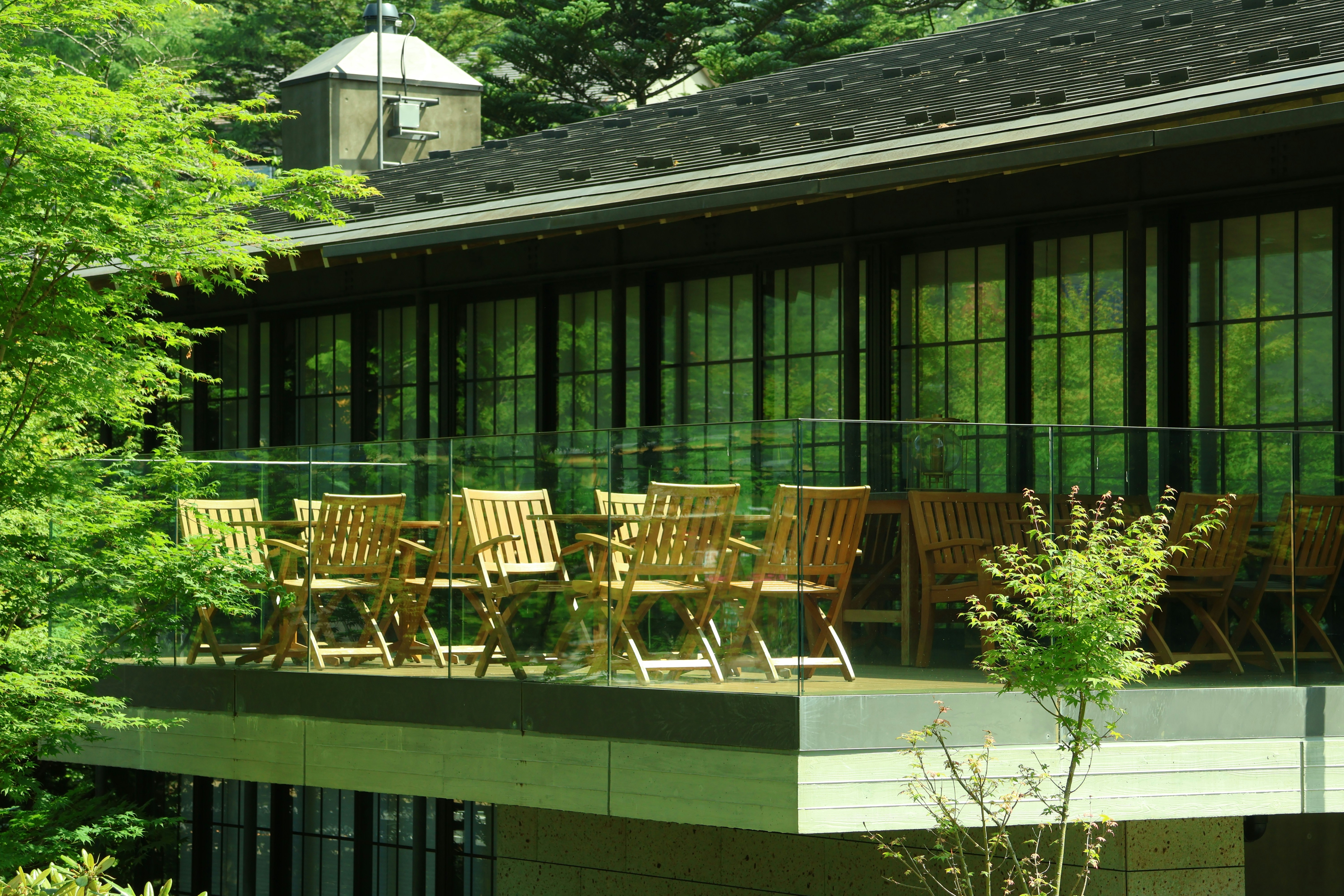 A modern balcony with chairs and trees.
