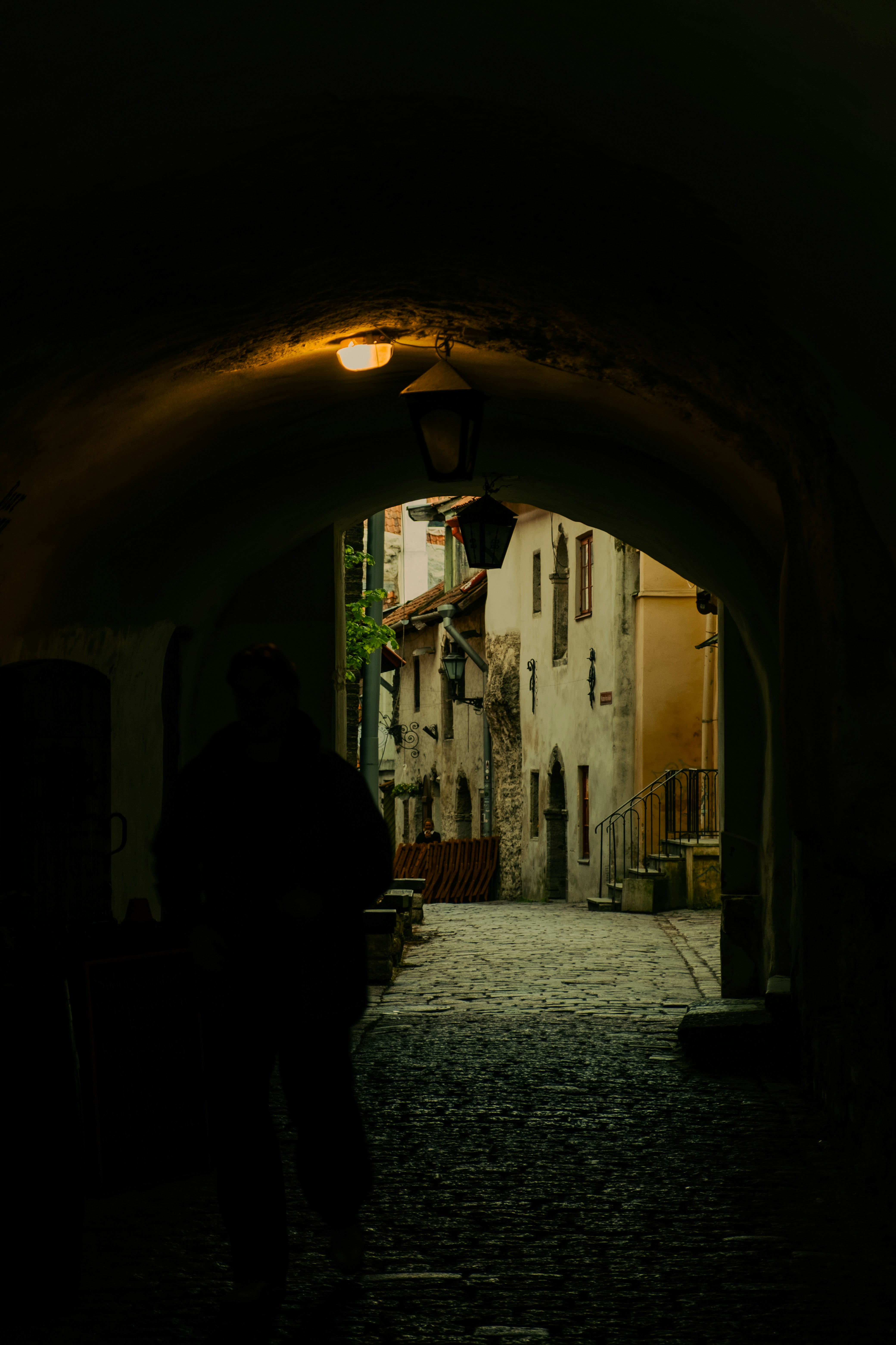 Silhouette of a person walks through an archway.