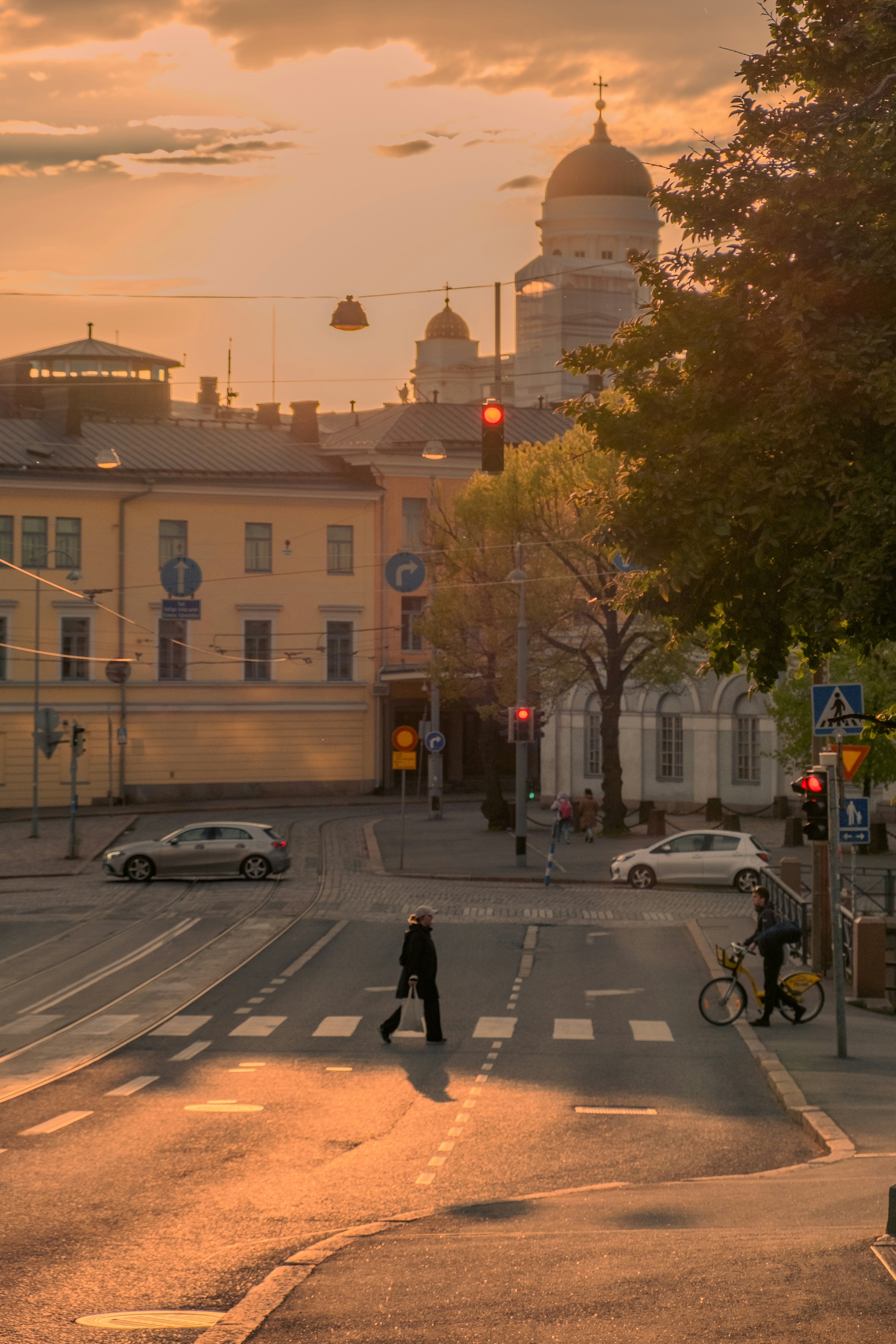City scene at sunset with people crossing the street.