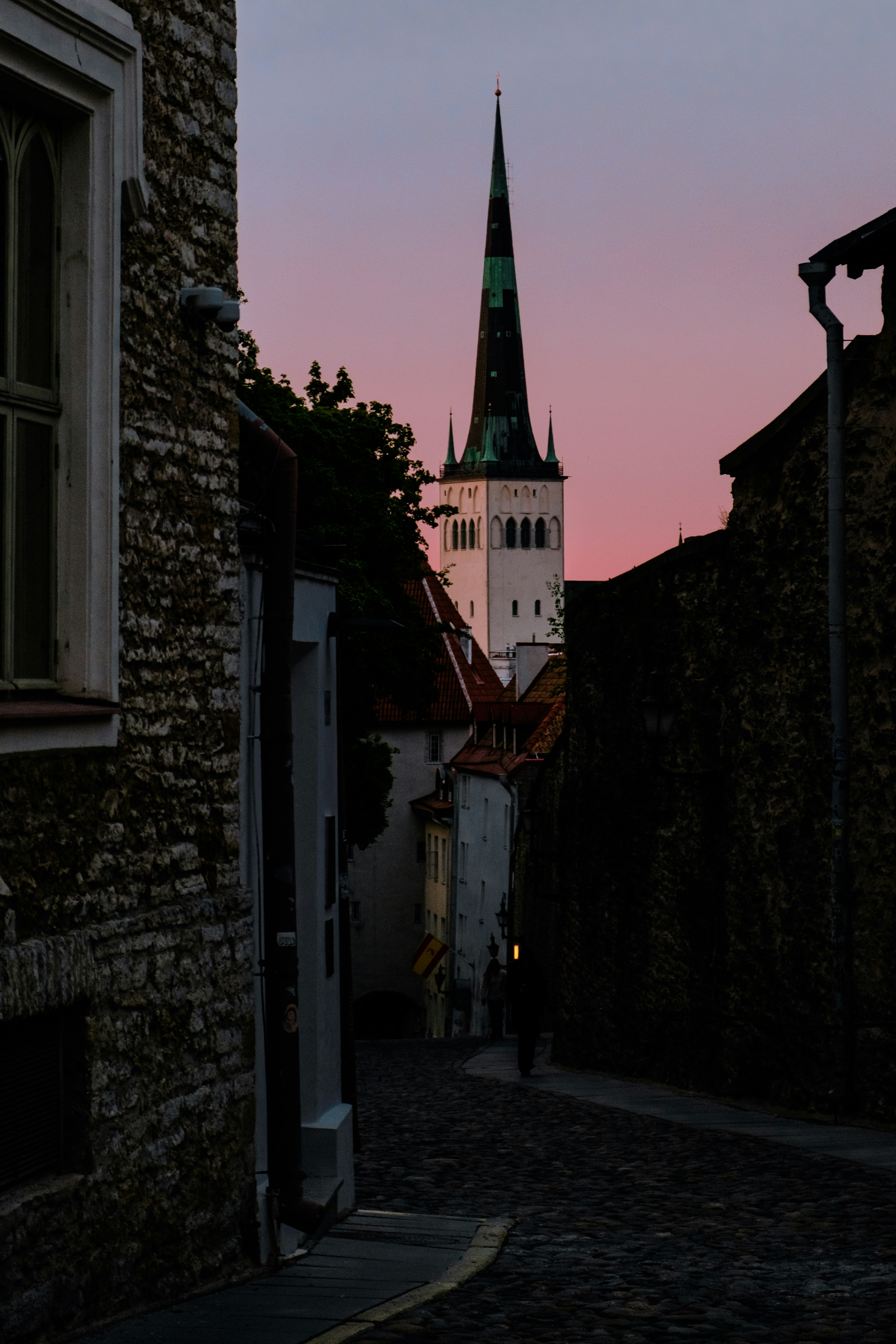 Cobblestone street leads to a church steeple at dusk.