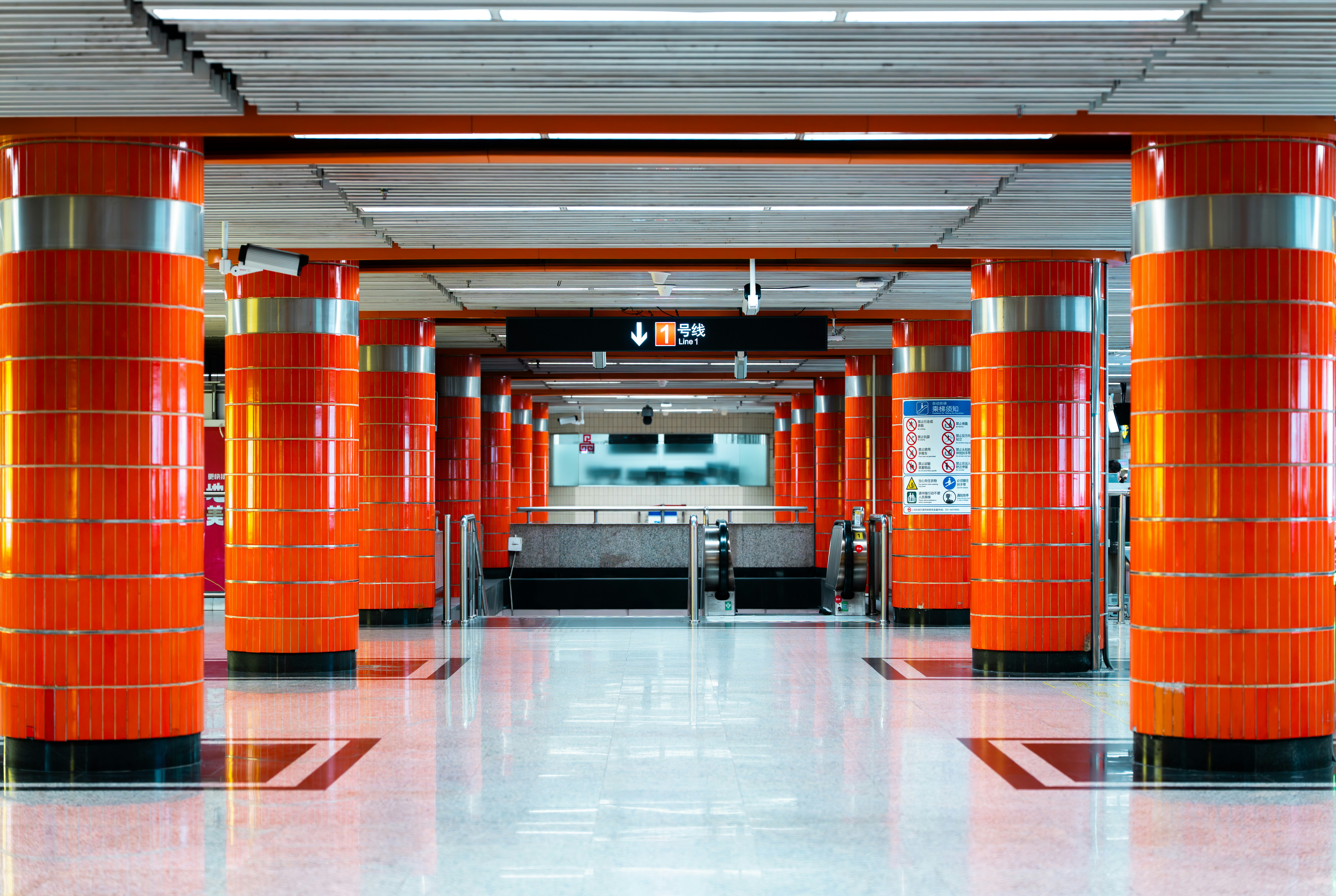 An orange subway station with pillars.