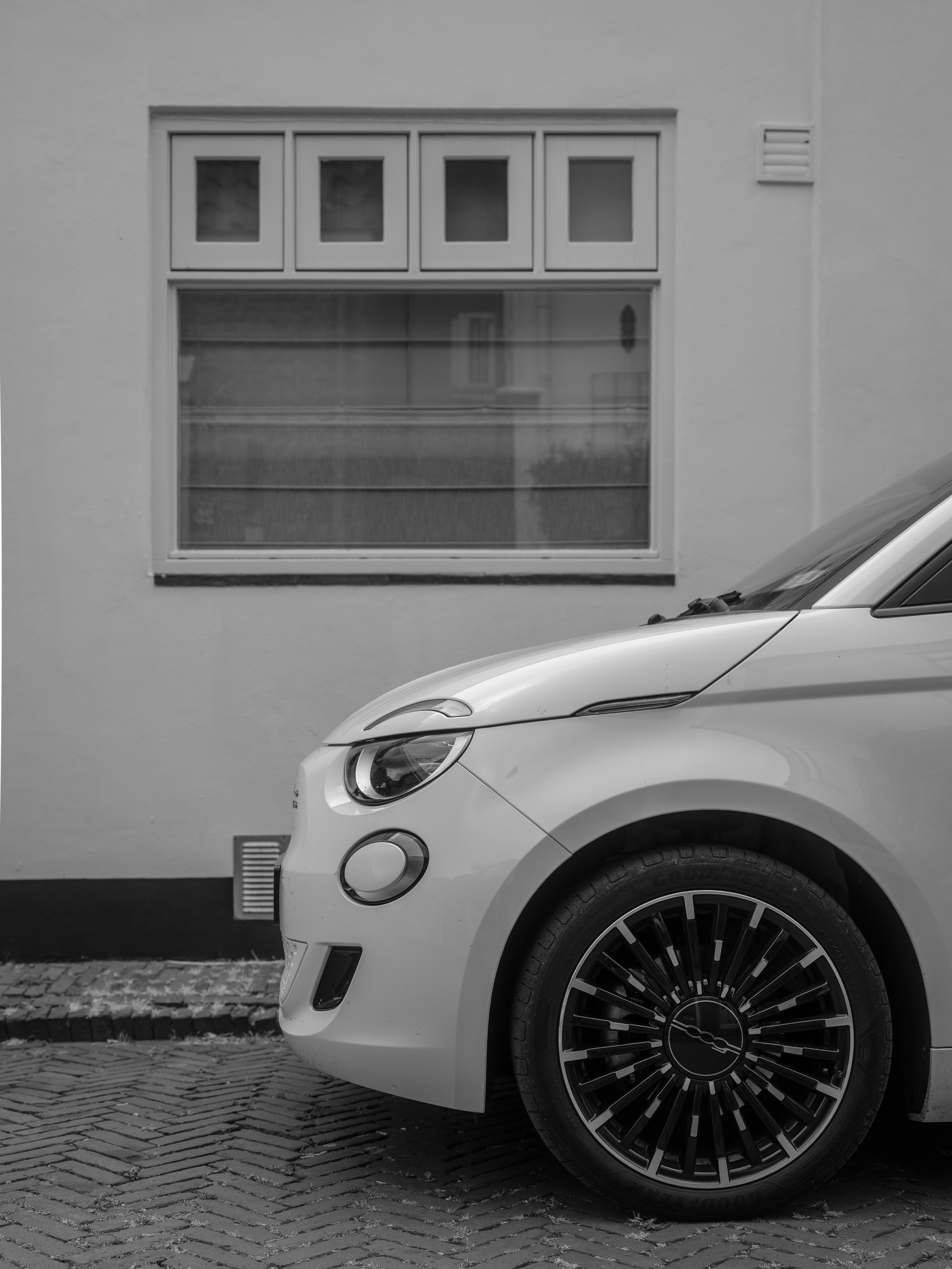 Front-wheel Portrait of a Compact Car Beside a Minimalist Wall