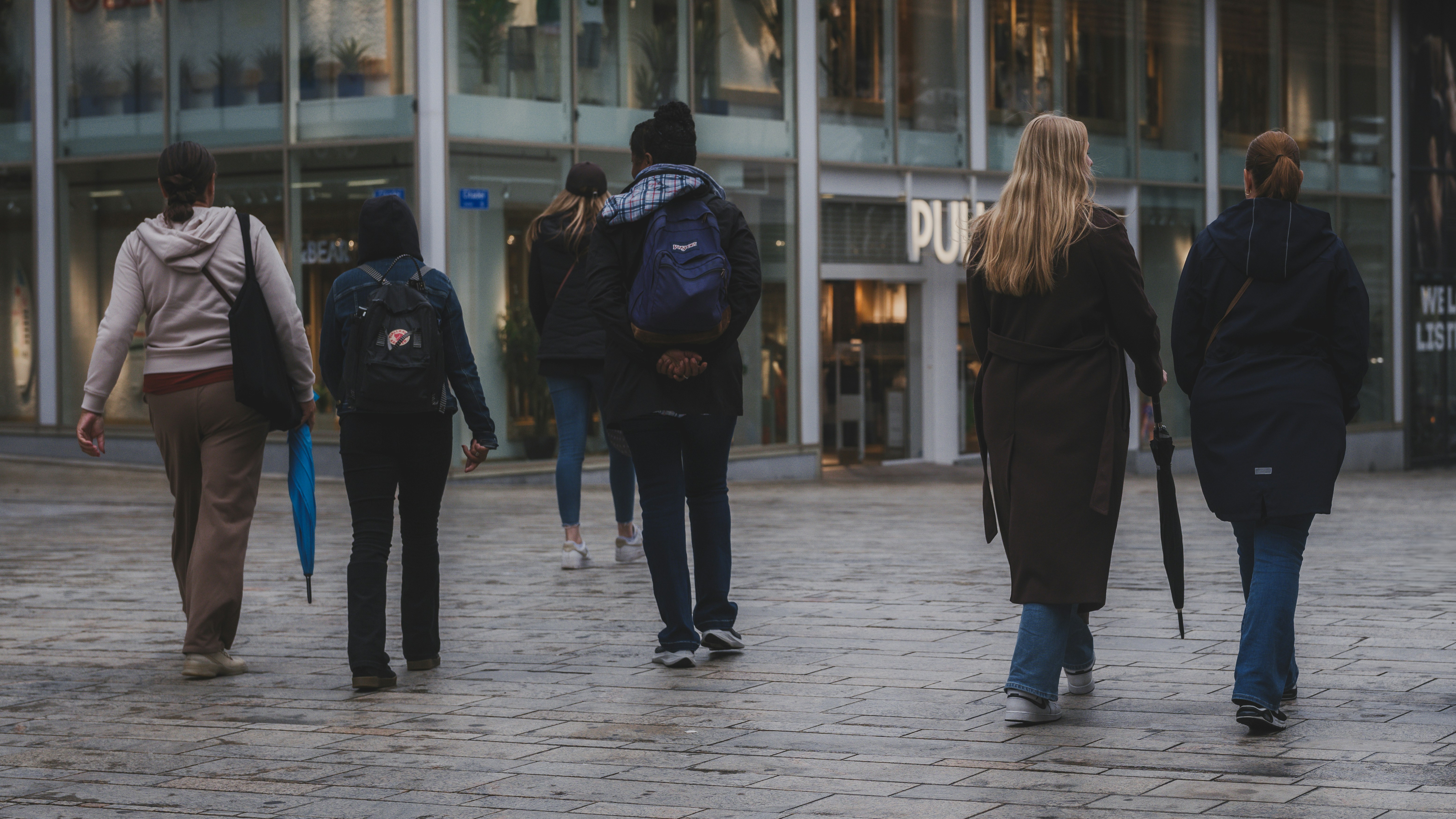 Group of People | People walk down a city street toward a store.