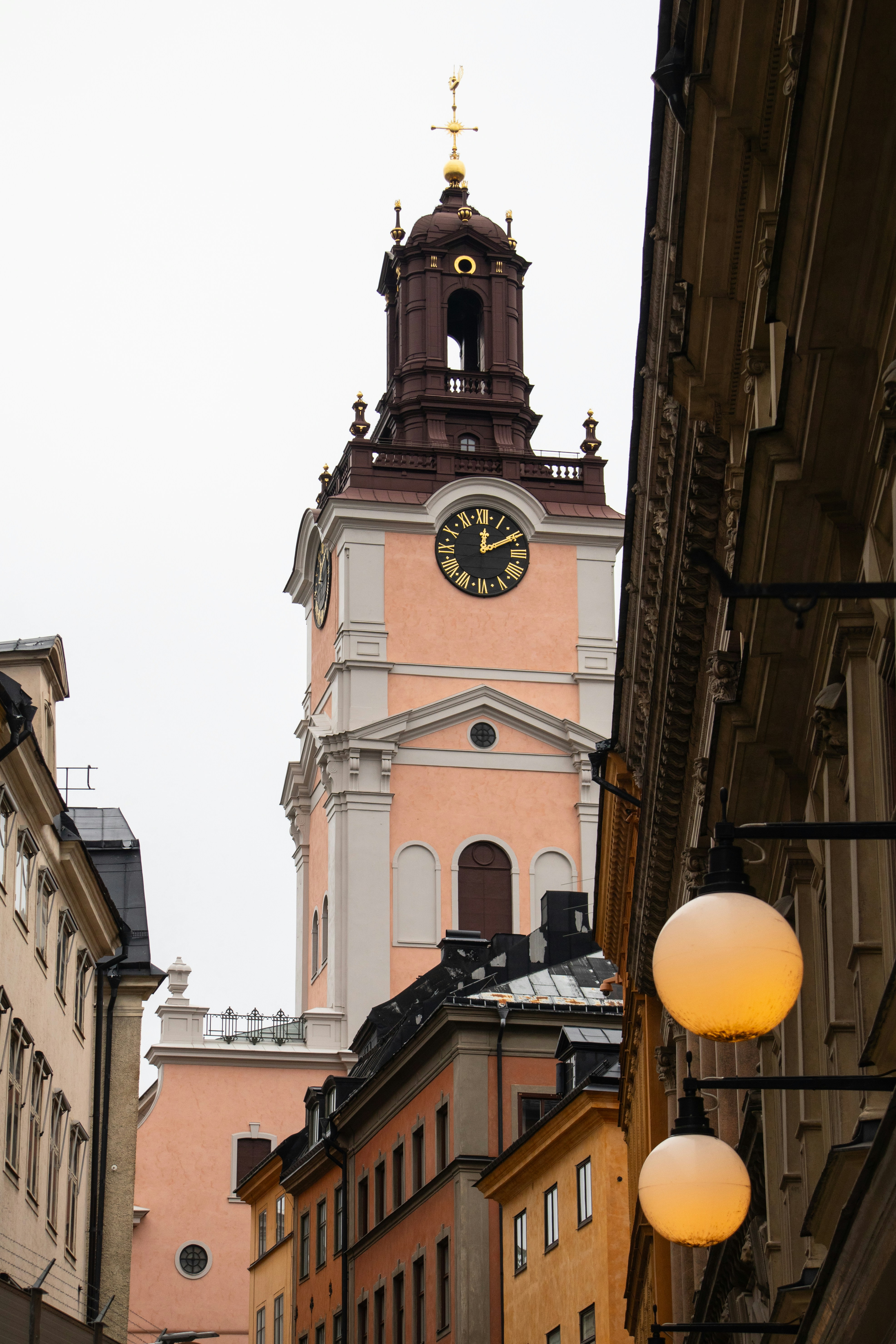 Historic clock tower rising above narrow streets, framed by charming buildings in a quaint urban setting.