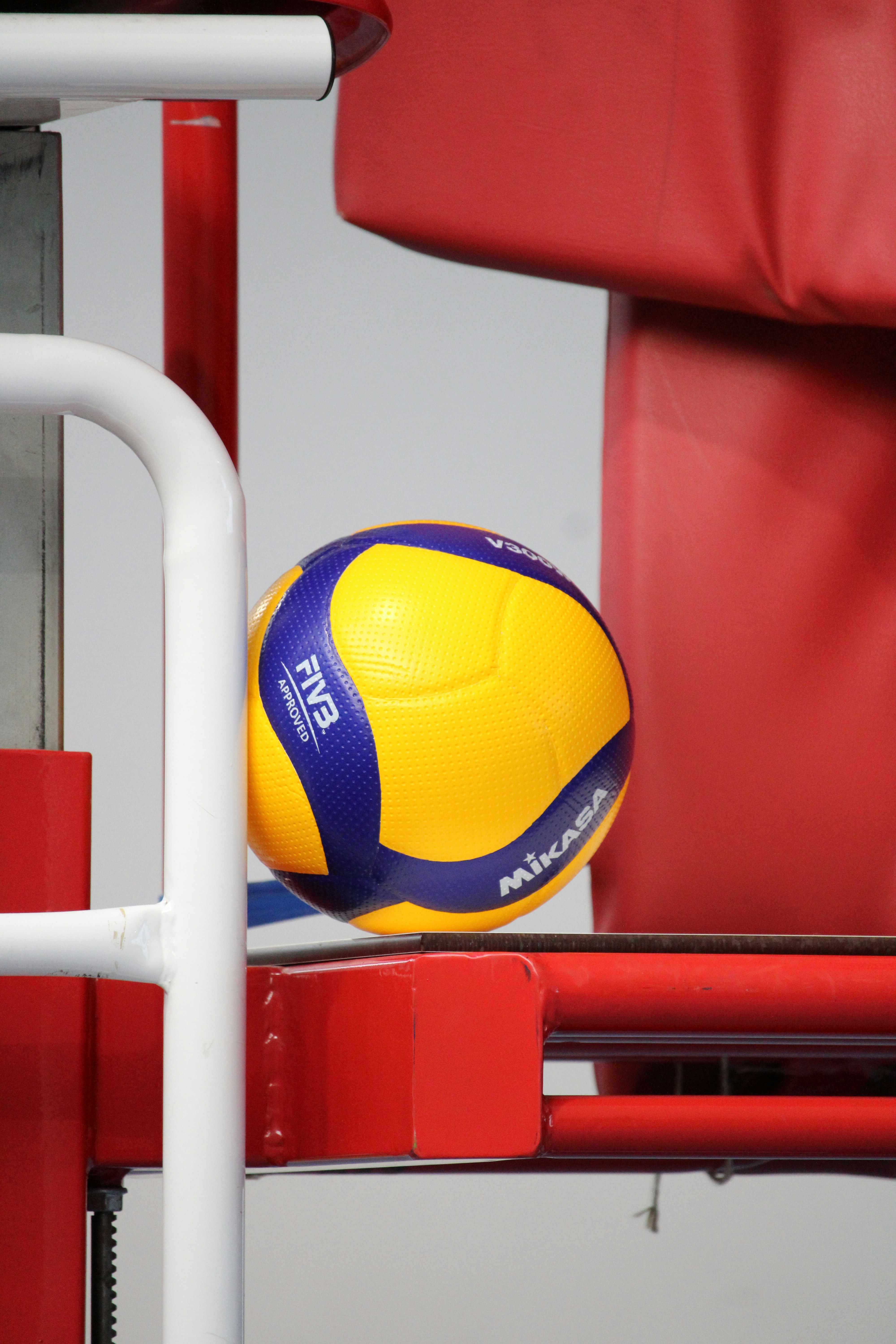 Volleyball rests on a red support near the net.