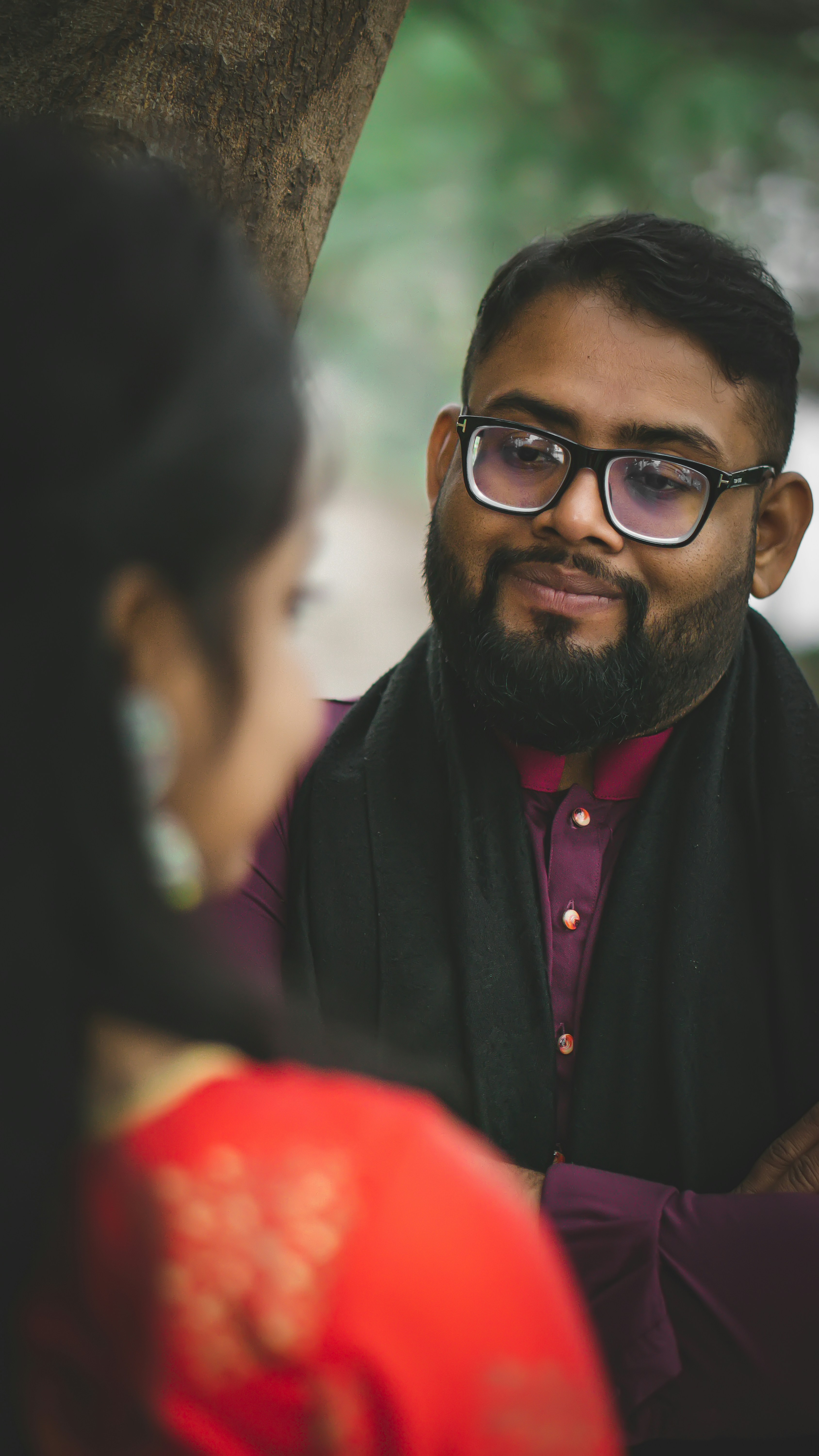 A man gazes thoughtfully at a woman, creating an intimate atmosphere amidst a natural backdrop.