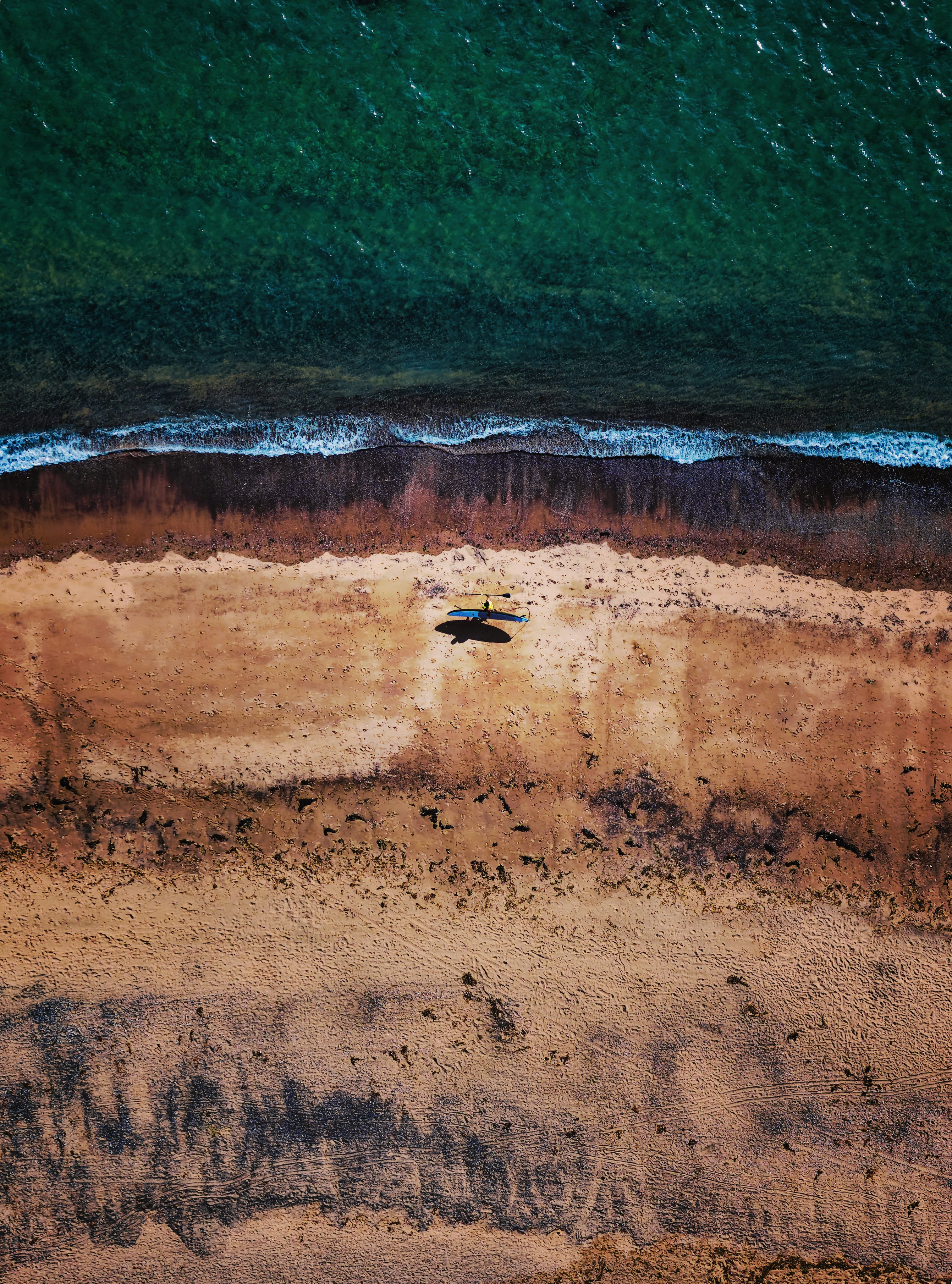 SUP boarder scouting the tides, Exmouth, Devon, UK | A surfboard rests on the sandy beach.