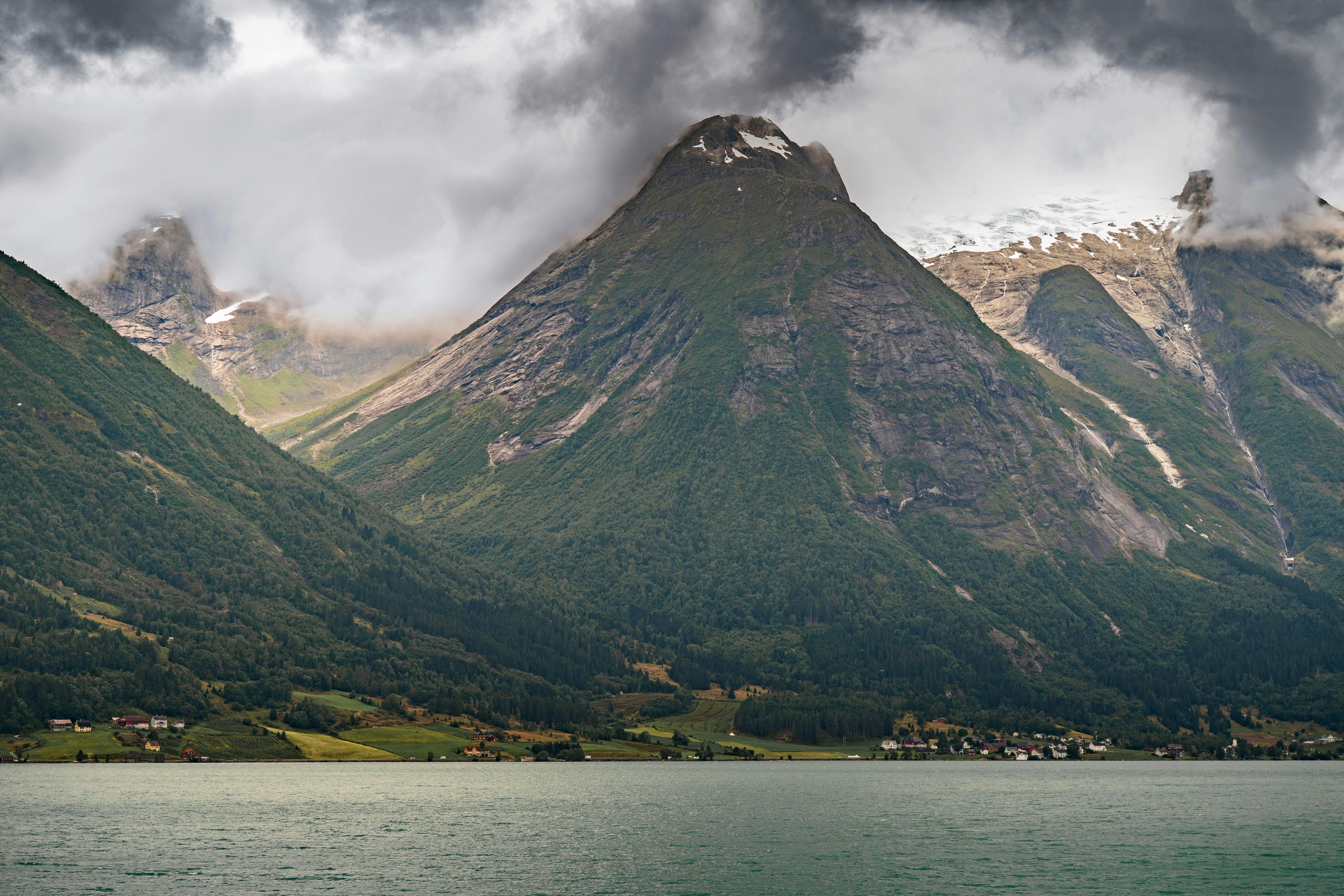 Mountains loom over a calm lake and misty skies.