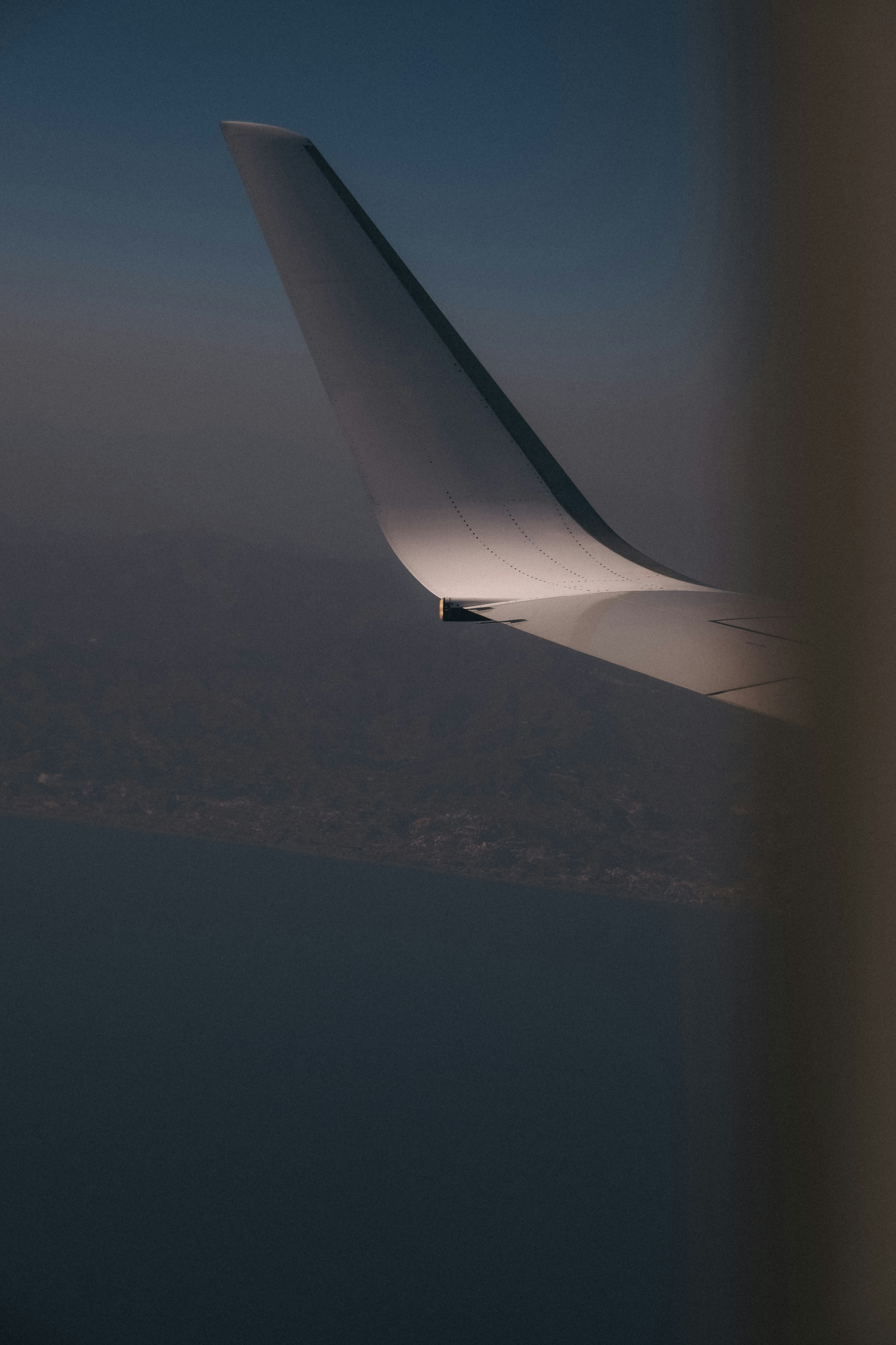 Airplane wing soaring above the land.
