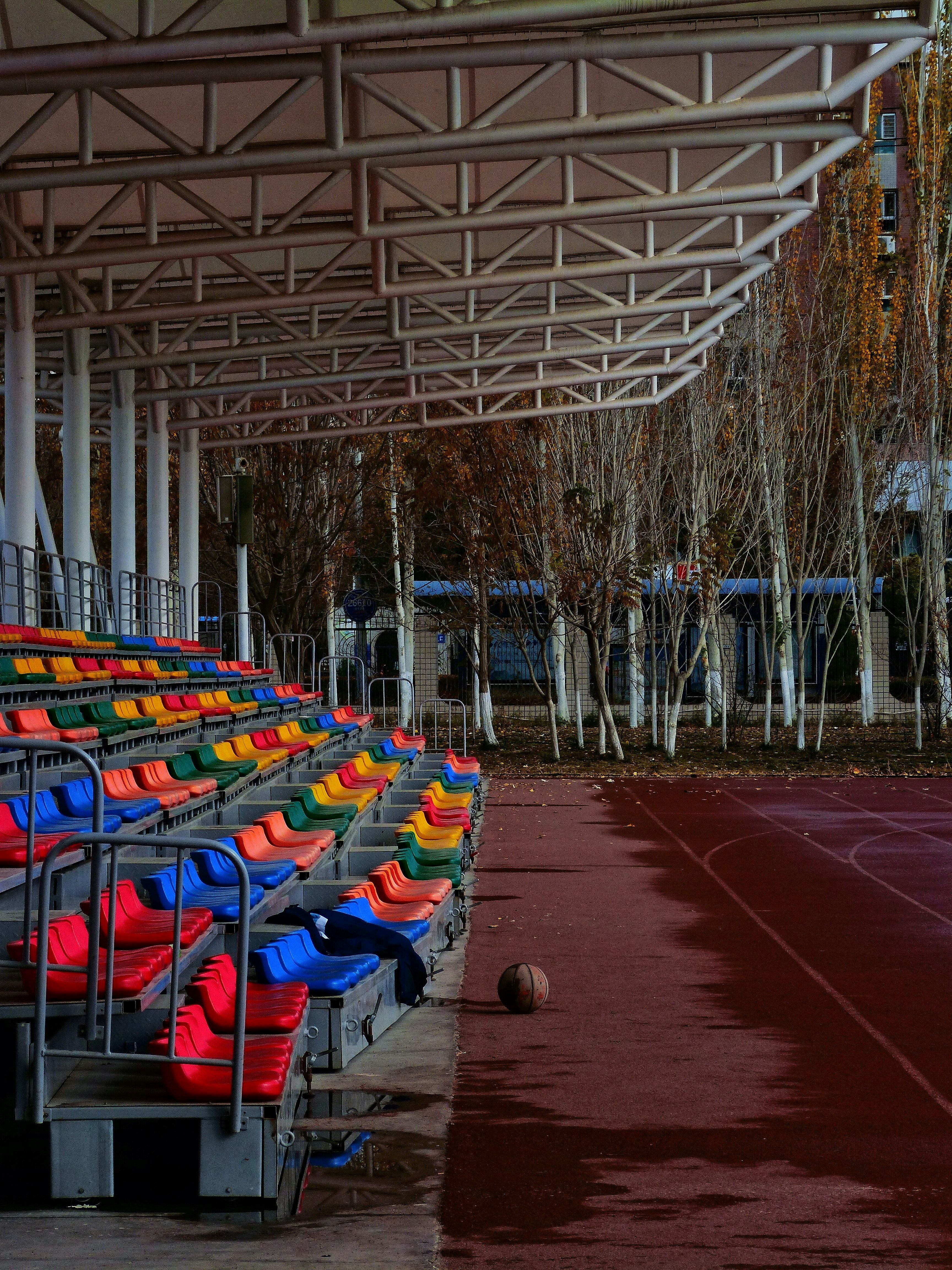 我的 My school playground. | Empty stadium seats stand under a protective canopy.