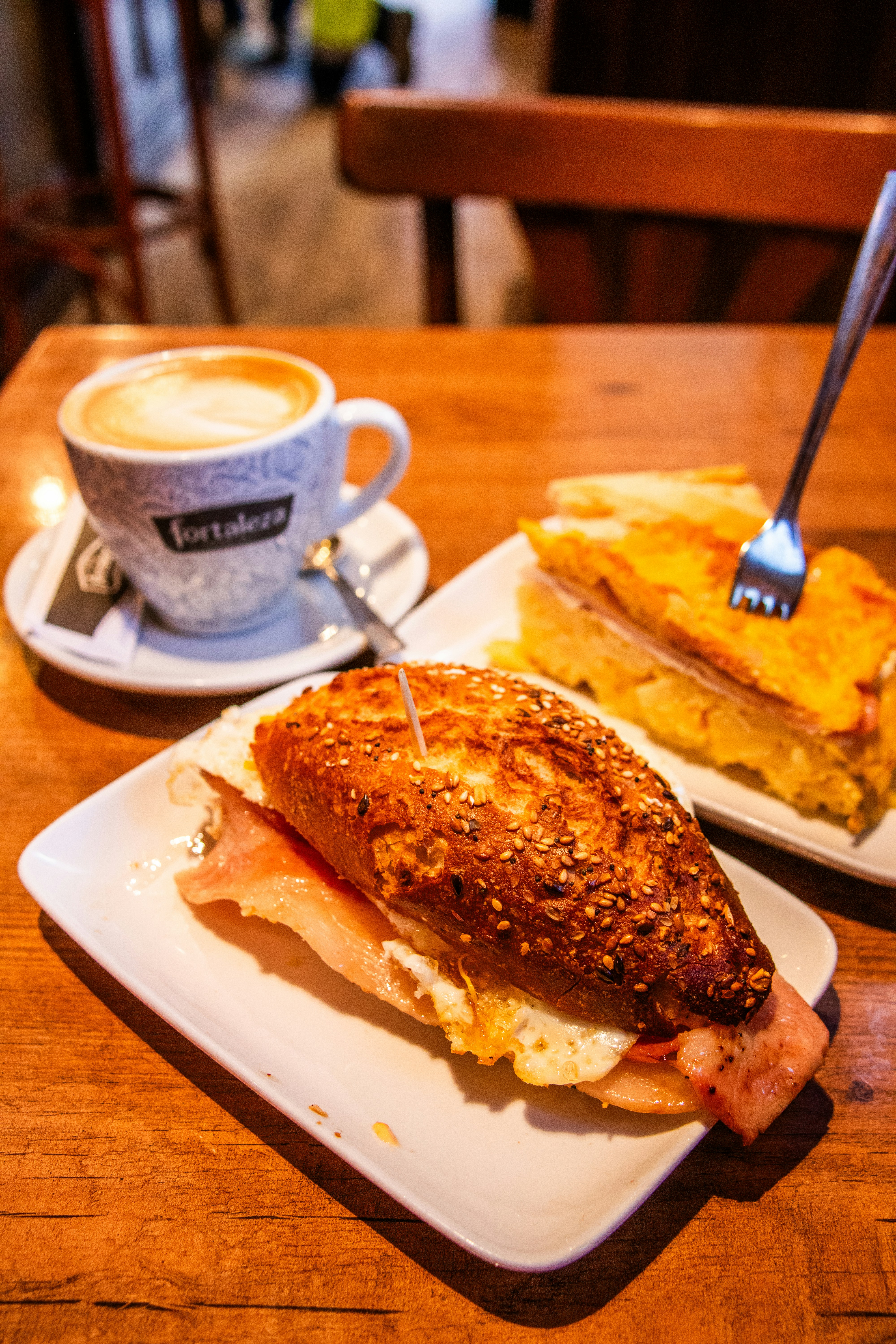 Coffee, sandwich, and tortilla on a wooden table.