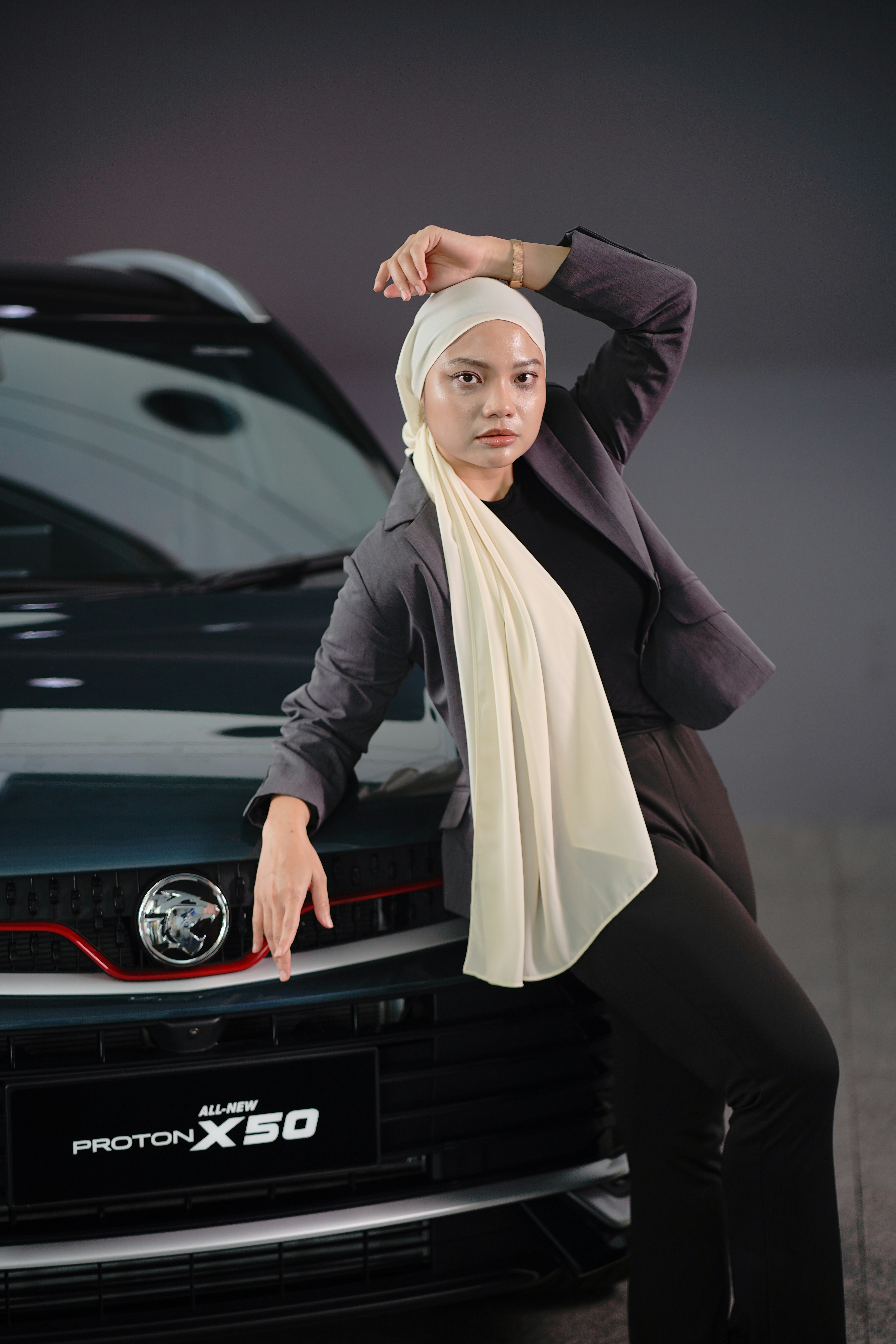 A woman poses by a proton x50 car.