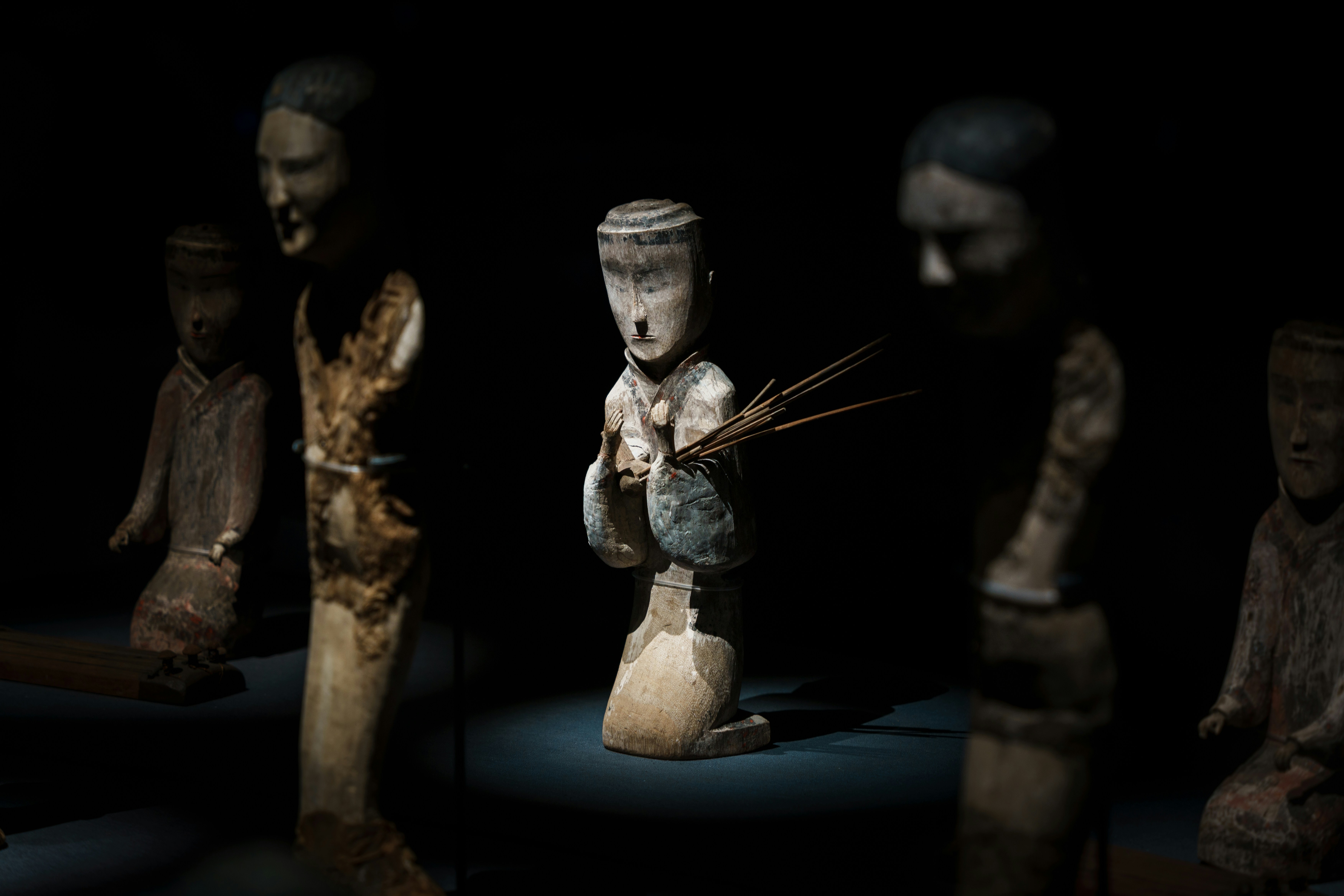 Ancient statues are illuminated in a dark room.