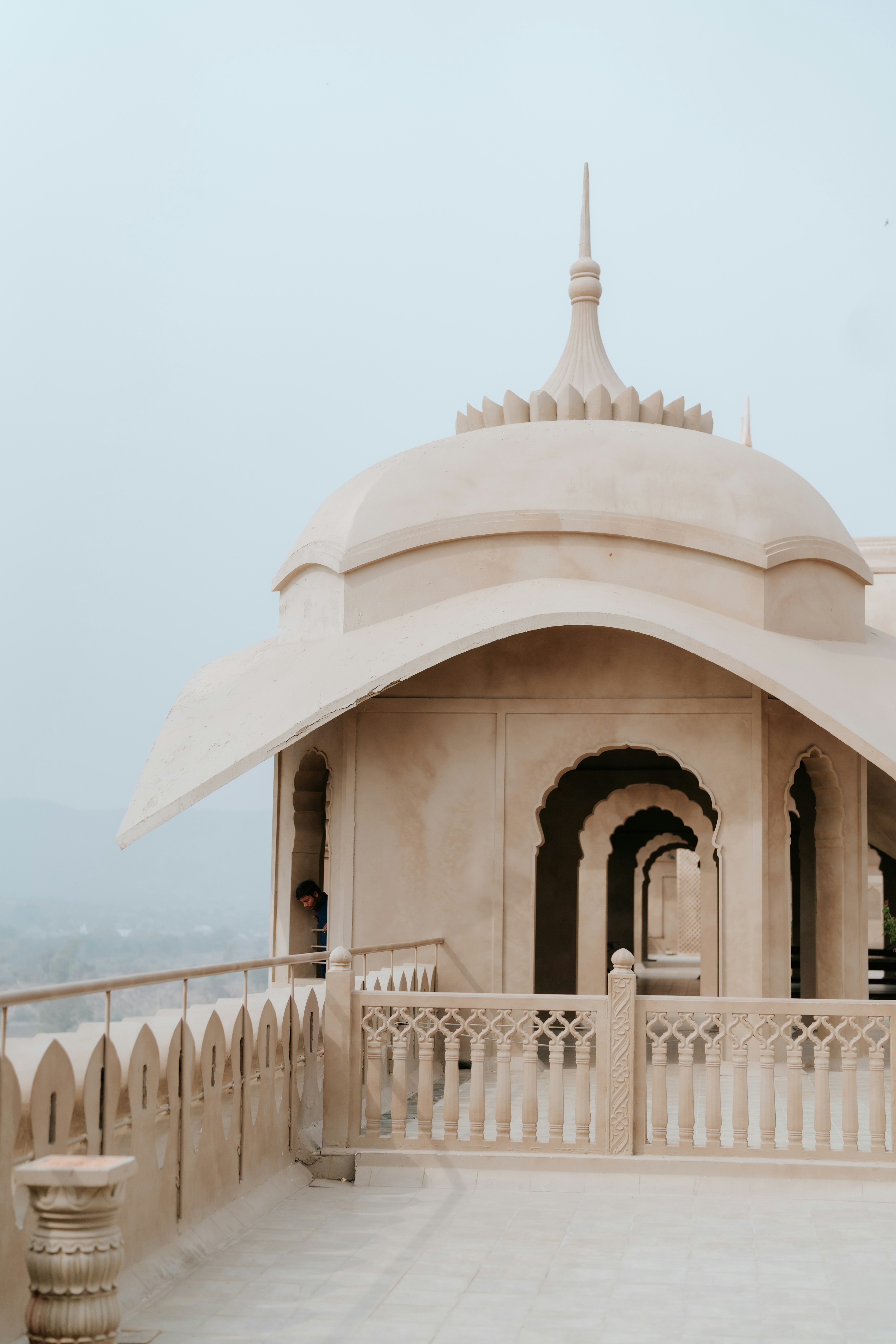 Intricate arches and domes of a historic structure, showcasing traditional design elements against a hazy backdrop.