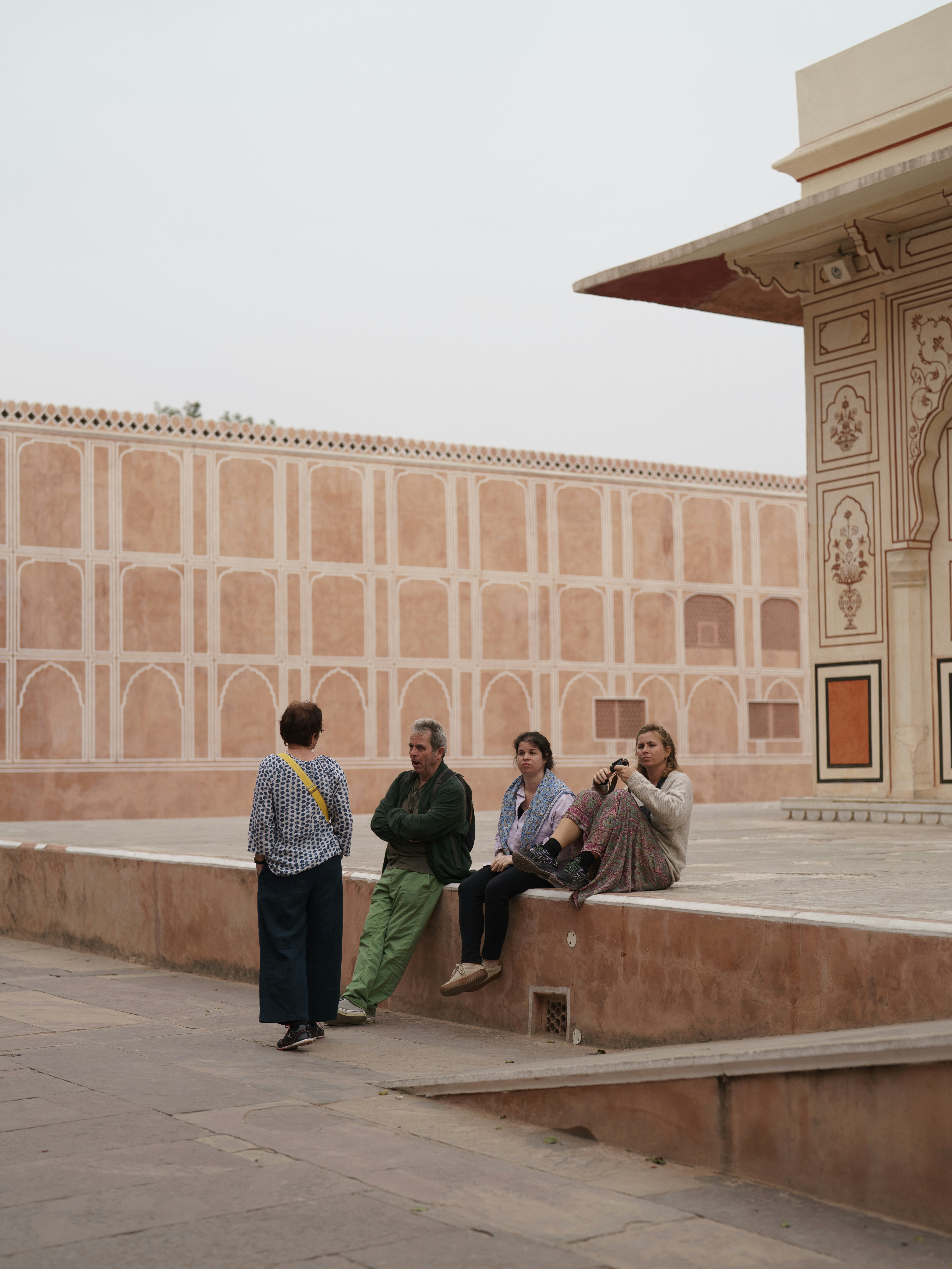 People gather and chat near a historical building.