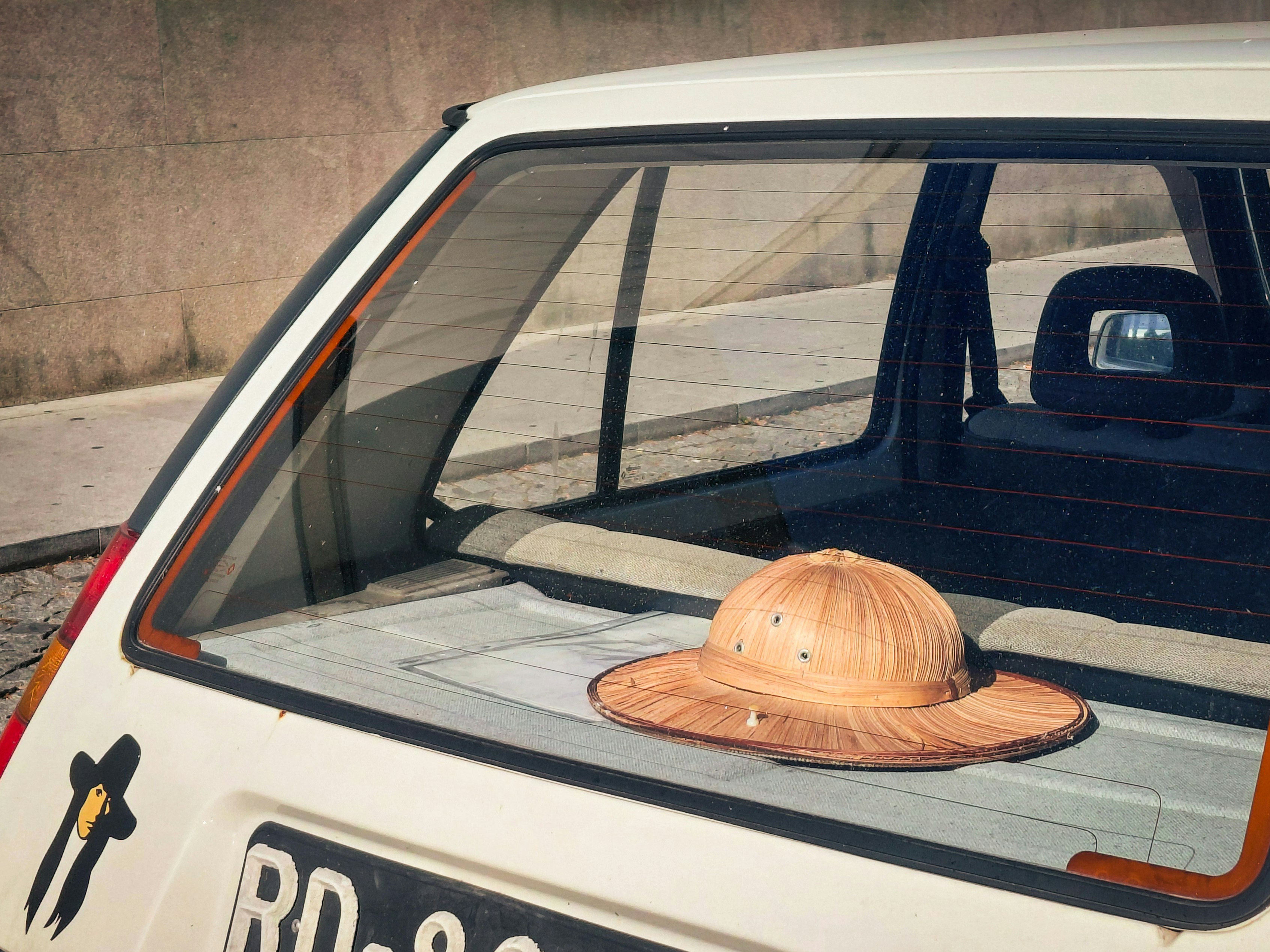 A hat sits inside the back of a car.