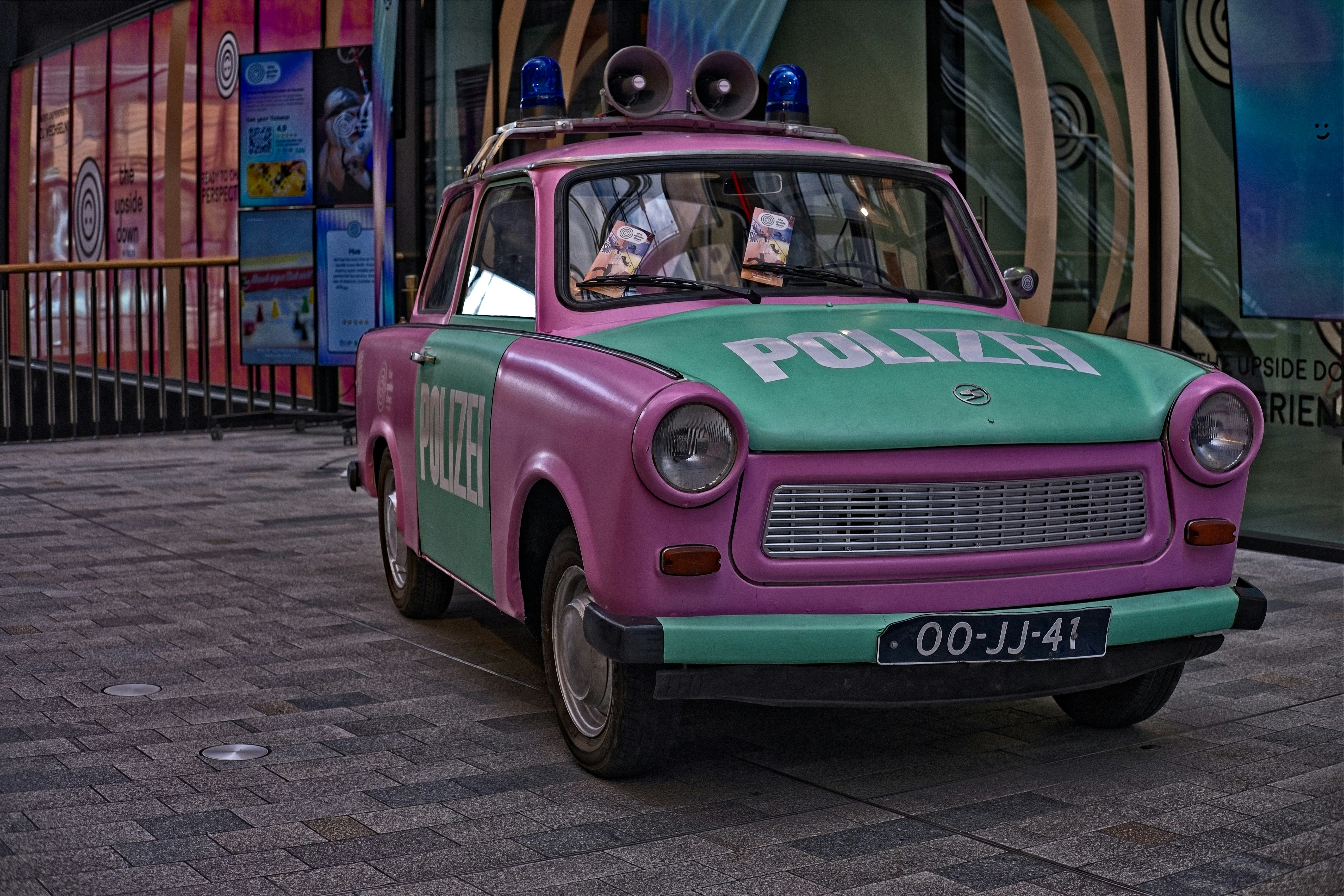 A pink and teal polizei car parked on a street.