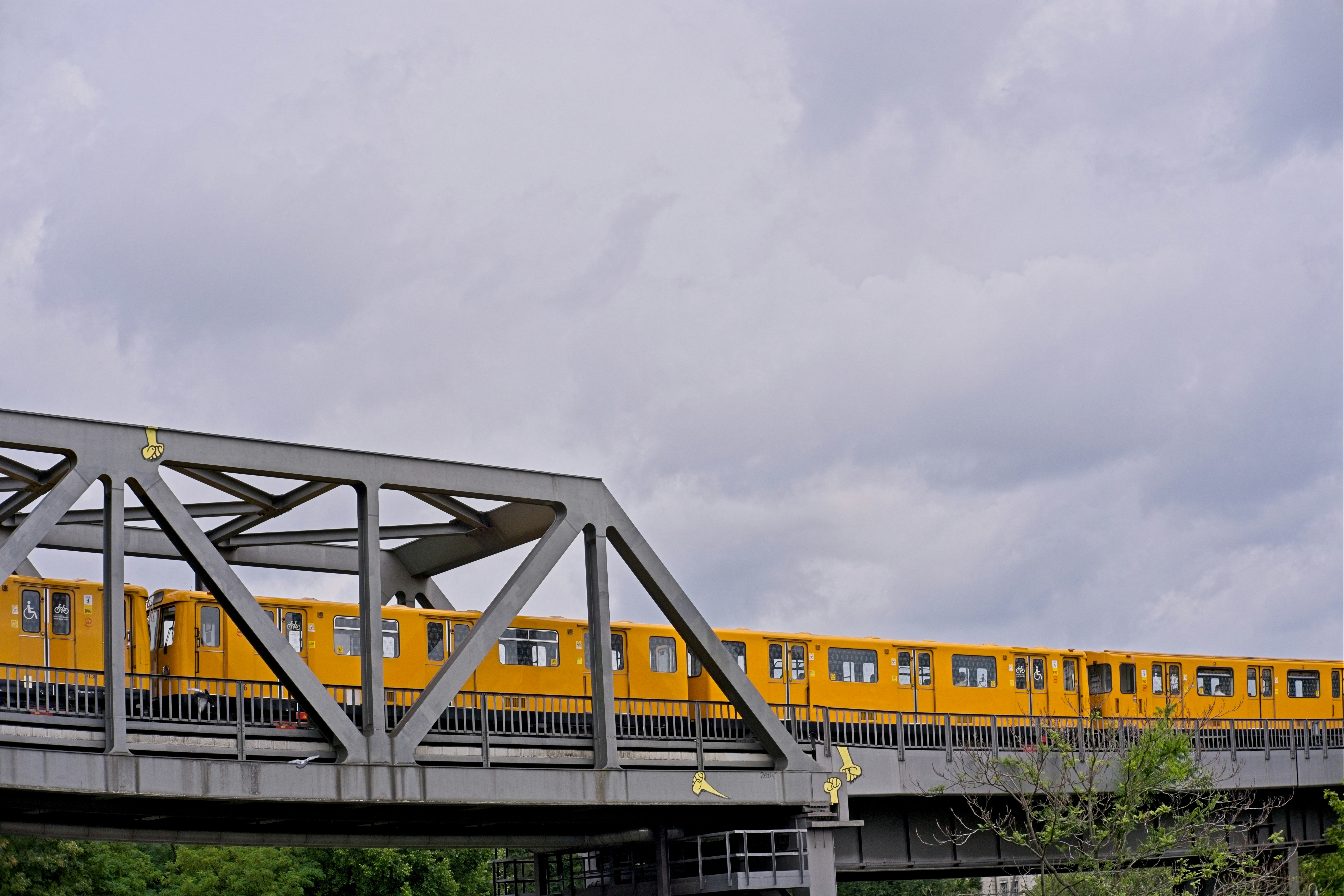 A yellow train travels on an overpass.