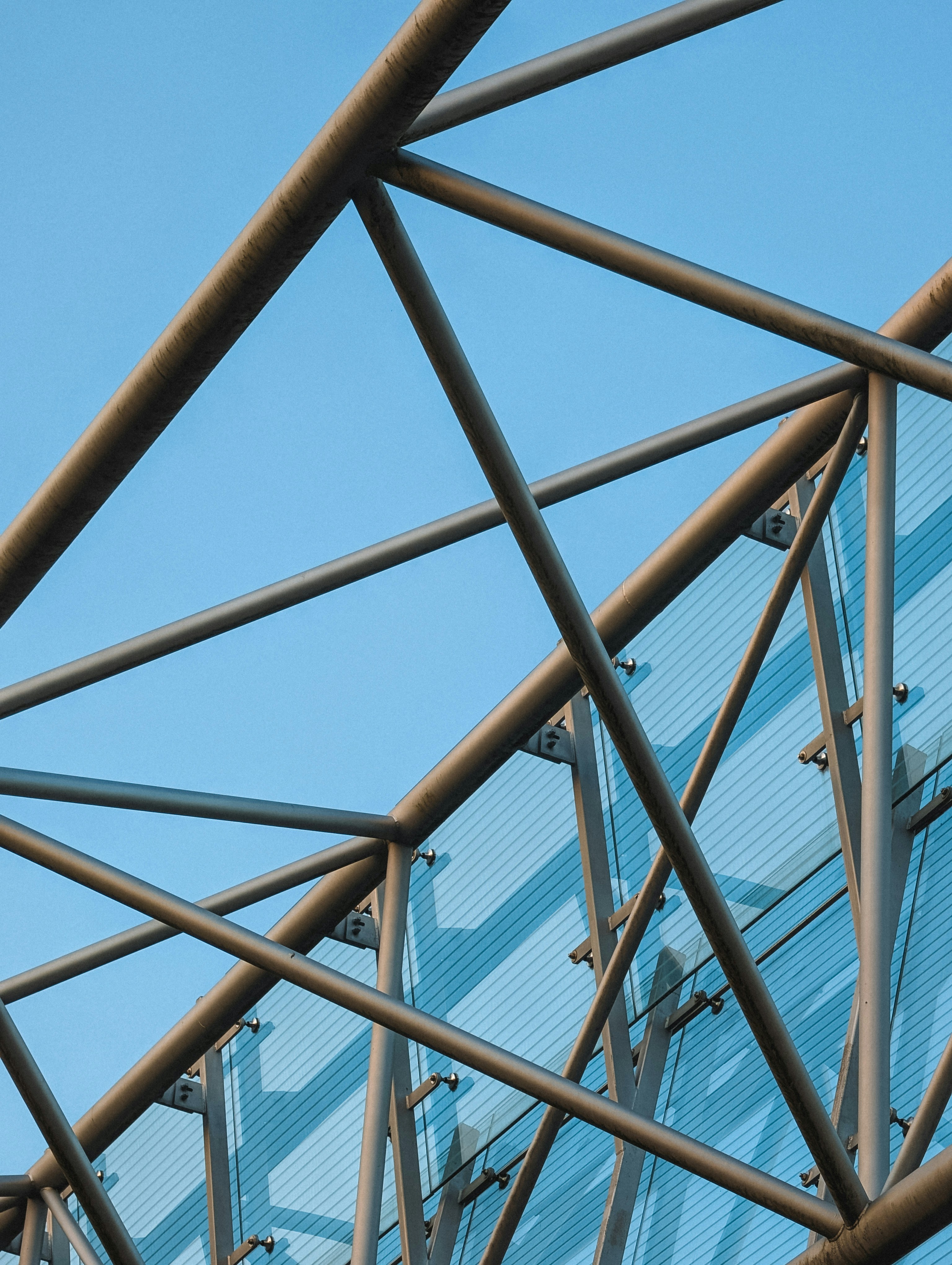 Diagonal beams frame the blue sky | Steel beams form a geometric structure against a blue sky.
