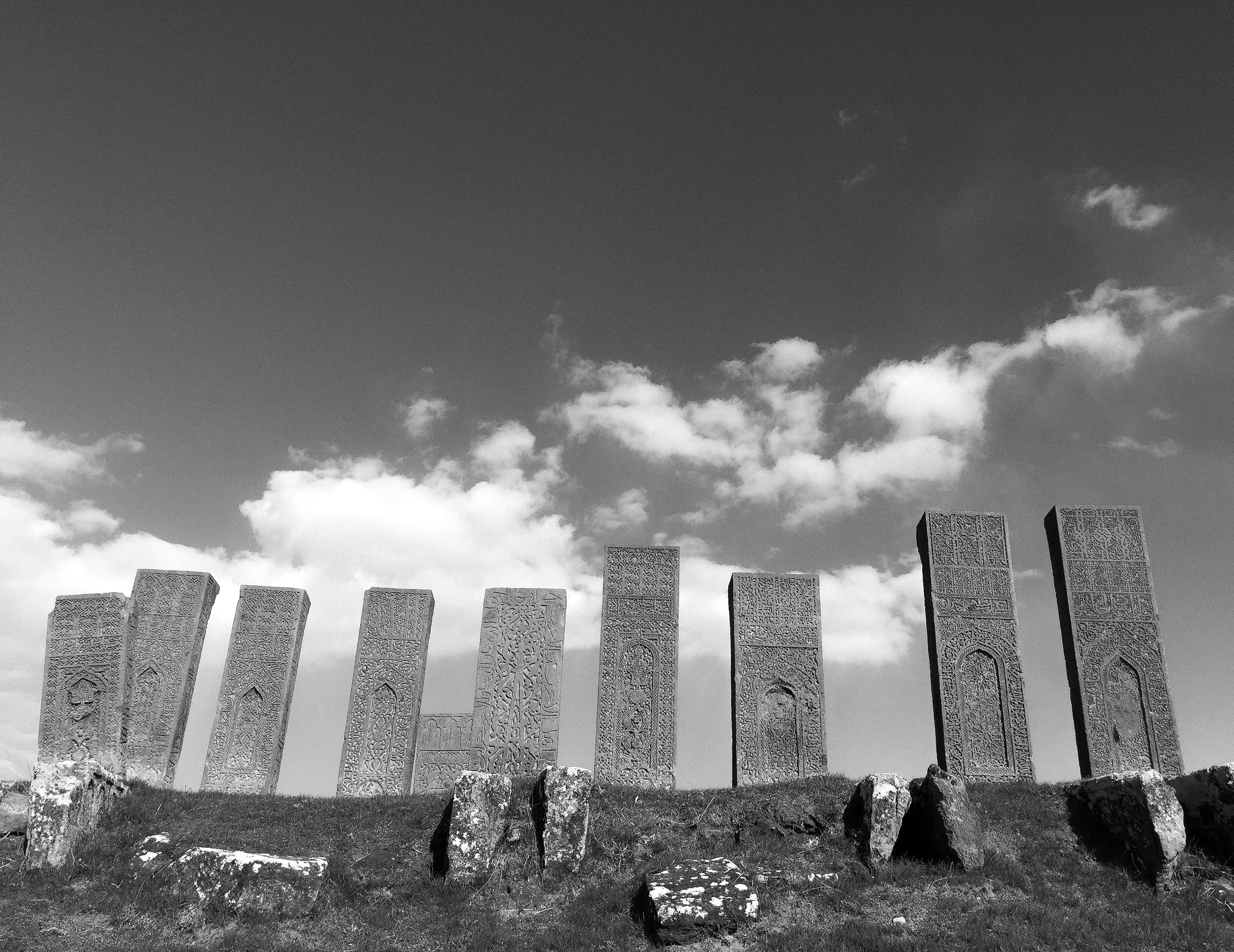 A series of standing stones etched with intricate designs against a cloudy sky, showcasing ancient craftsmanship and cultural significance.
