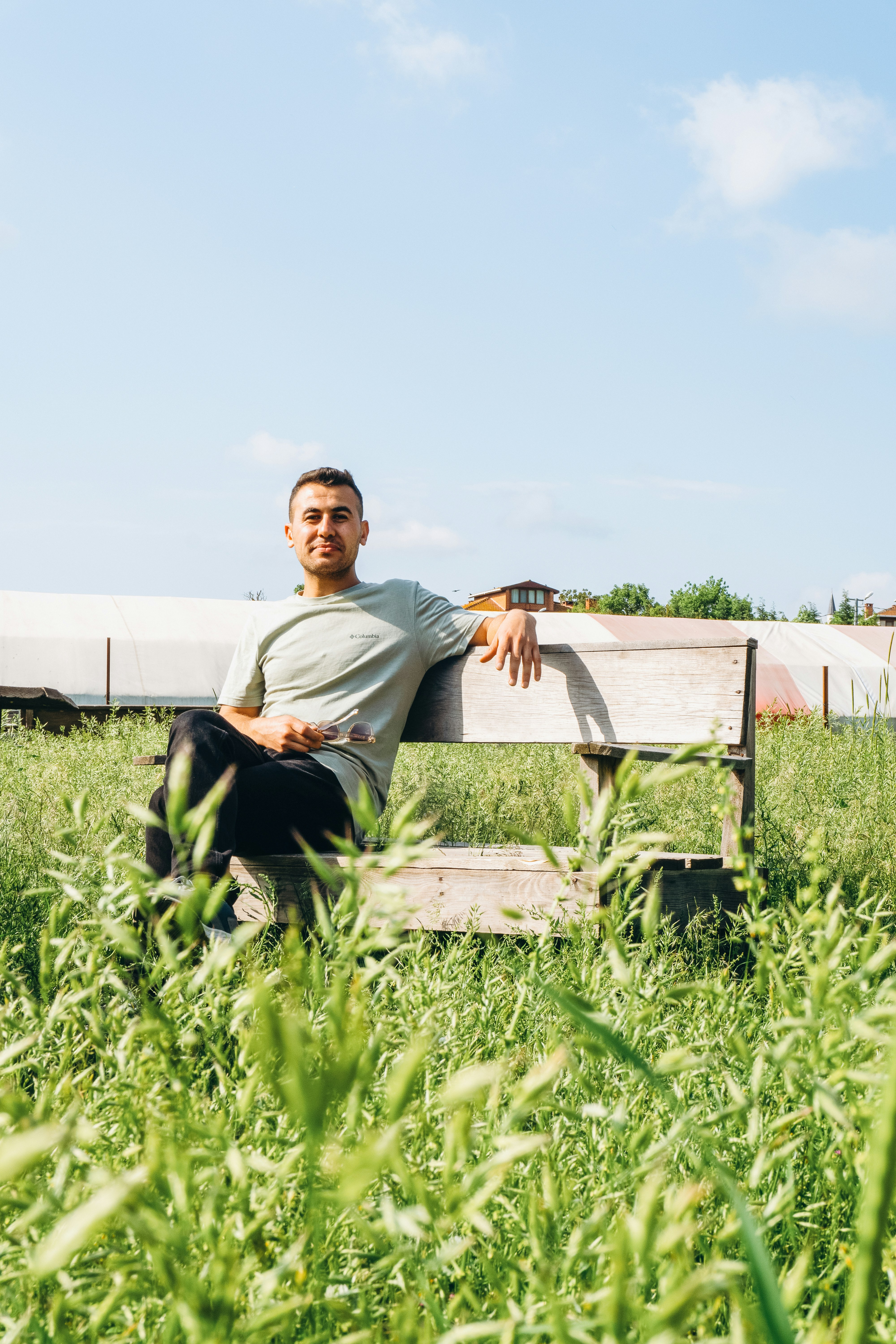 A man sits on a bench in nature.