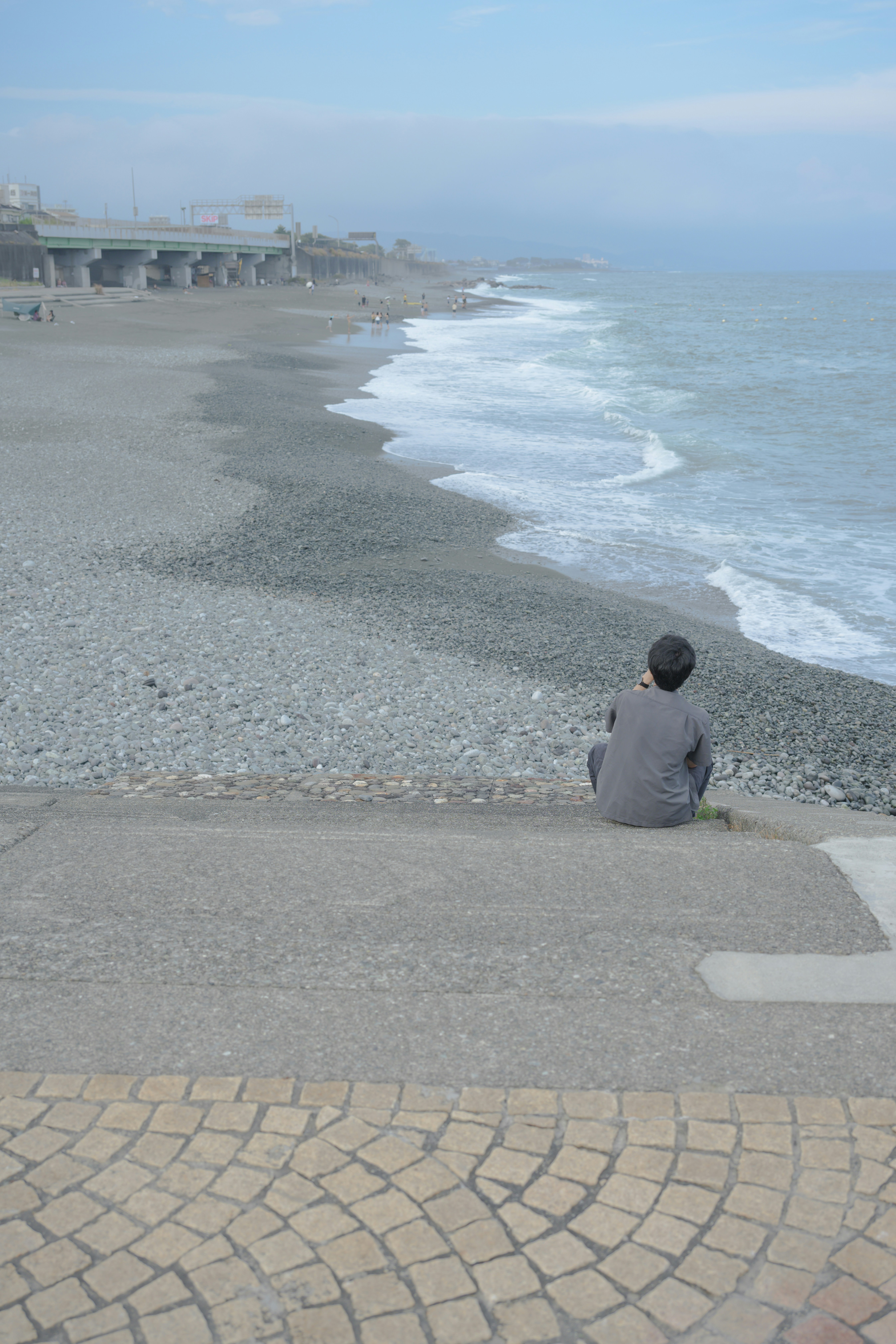 Person sits alone, gazing at the misty ocean.