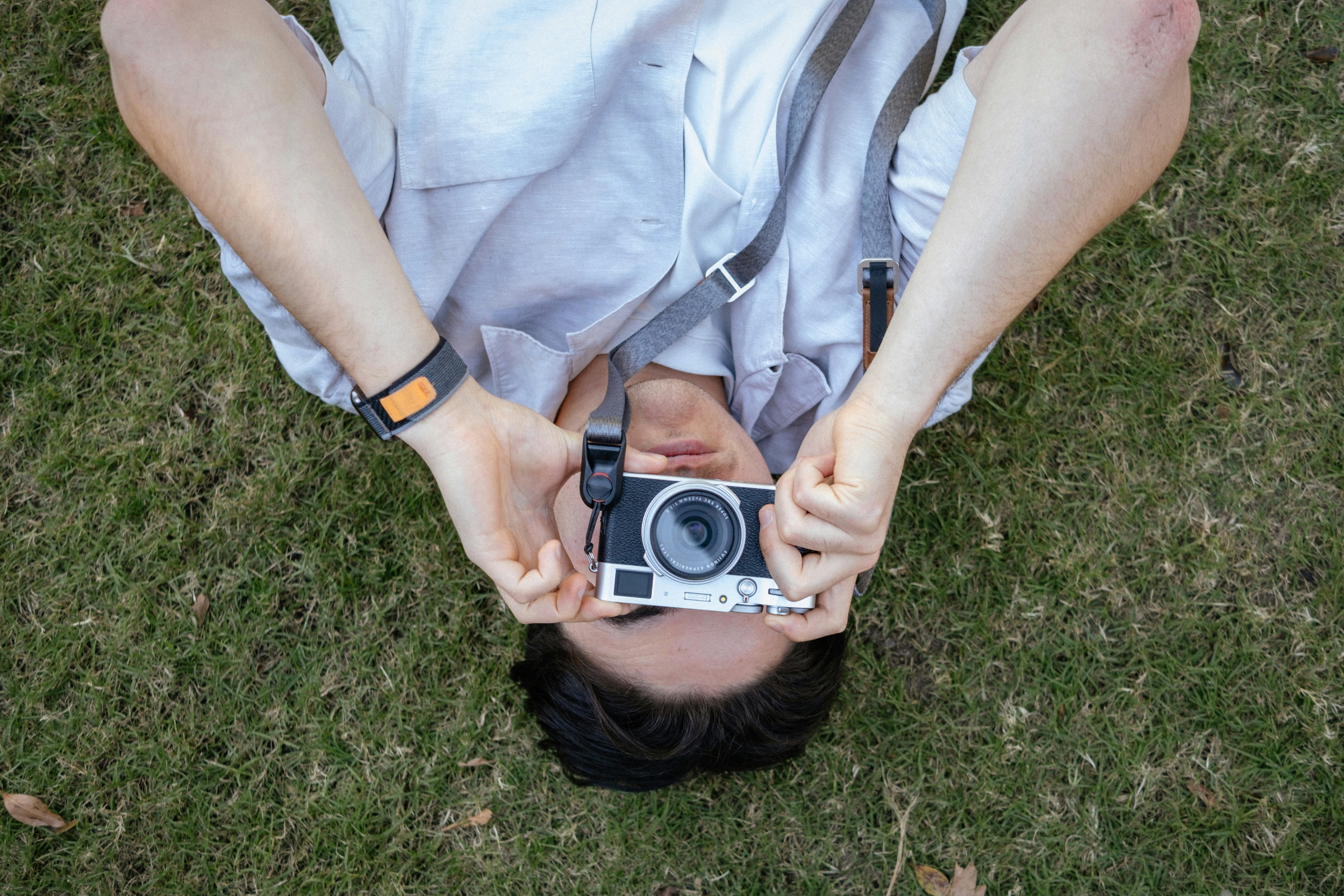 A person is lying on the grass with a camera.