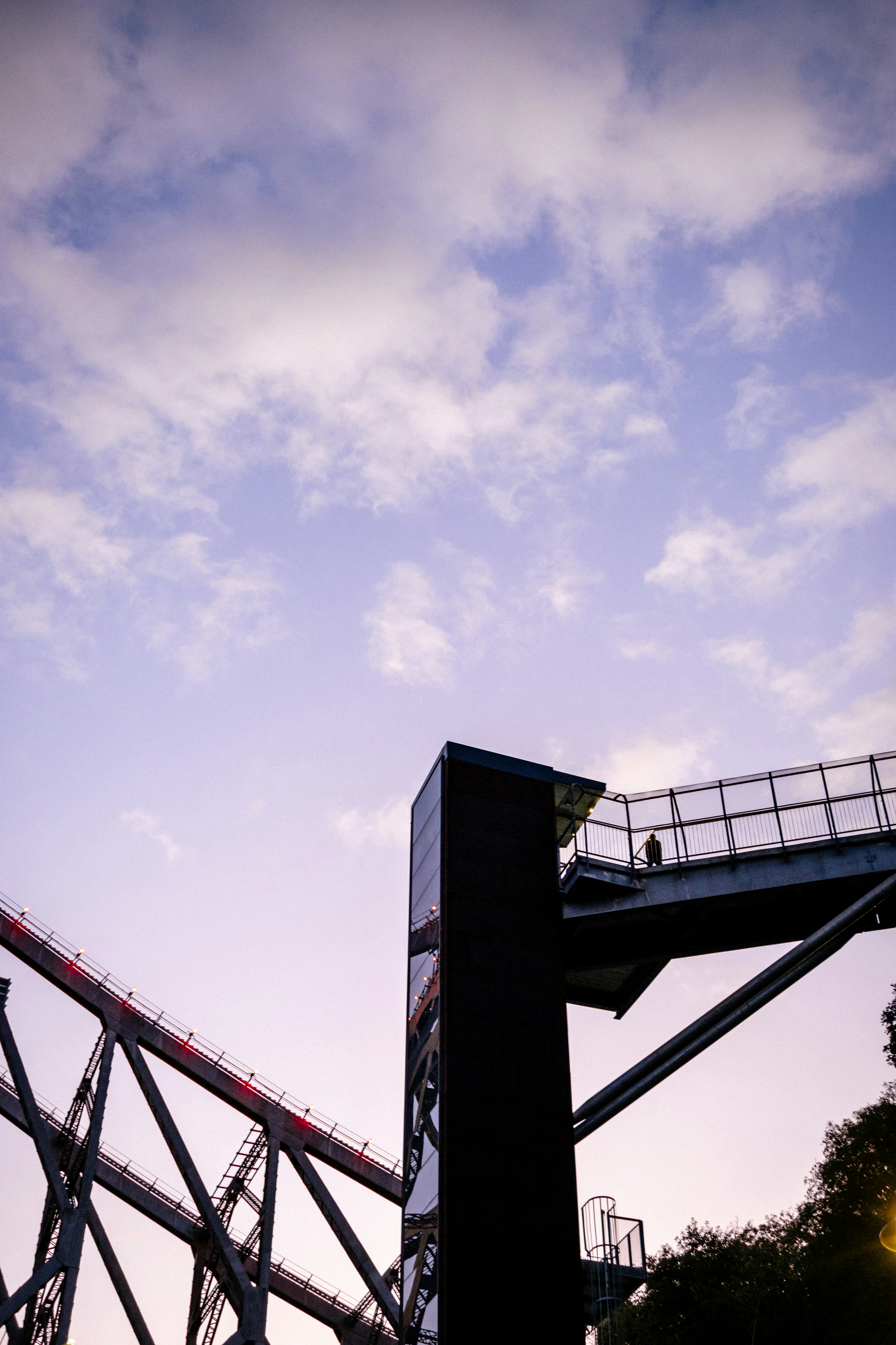 A bridge and tower against a purple sky.
