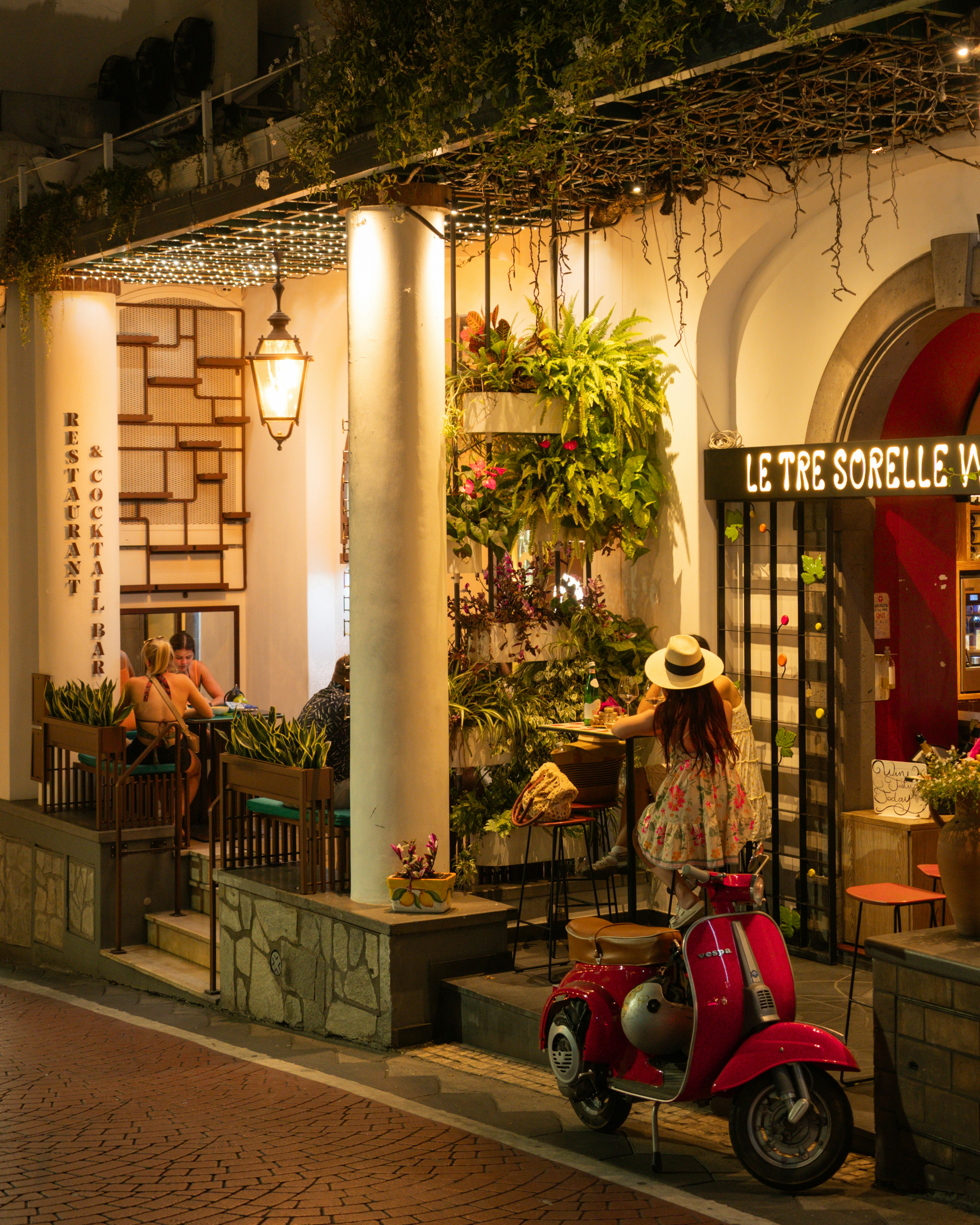 A woman poses by a scooter in front of a restaurant.