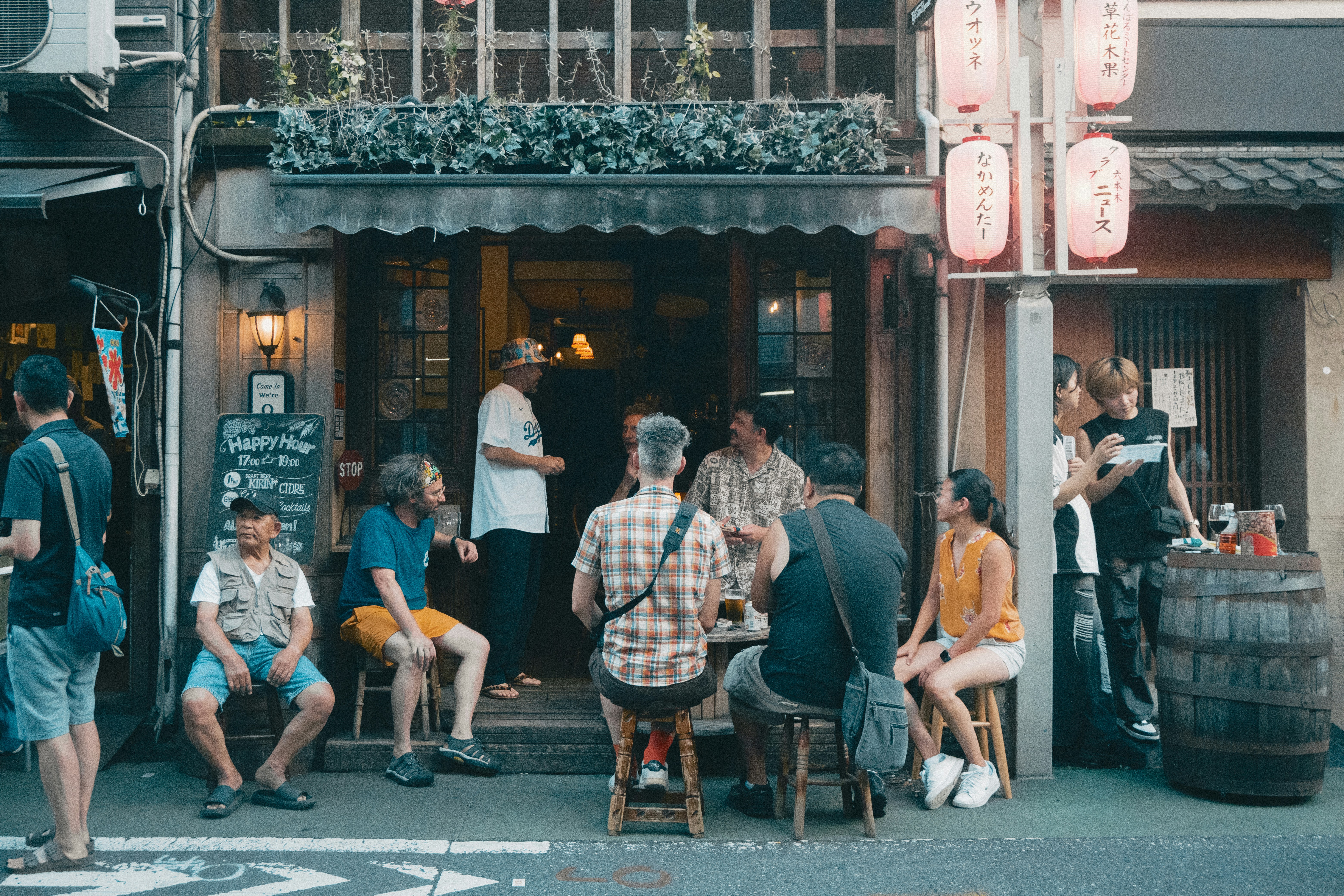 A lively scene outside a local tavern, featuring patrons engaged in conversation and enjoying their time together. The ambiance reflects a vibrant community atmosphere.