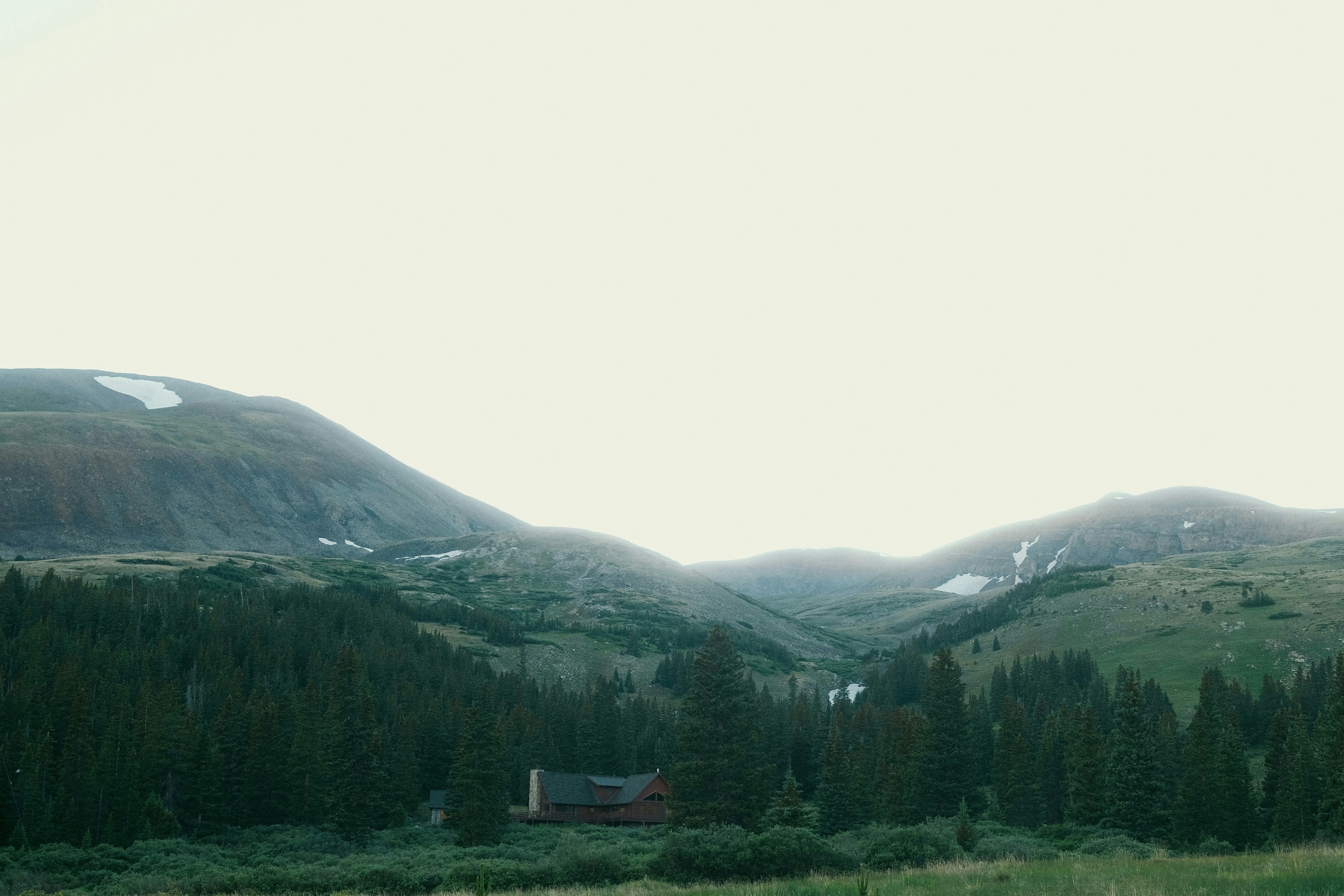Cabin in the woods | Mountains and a forest with a small building.