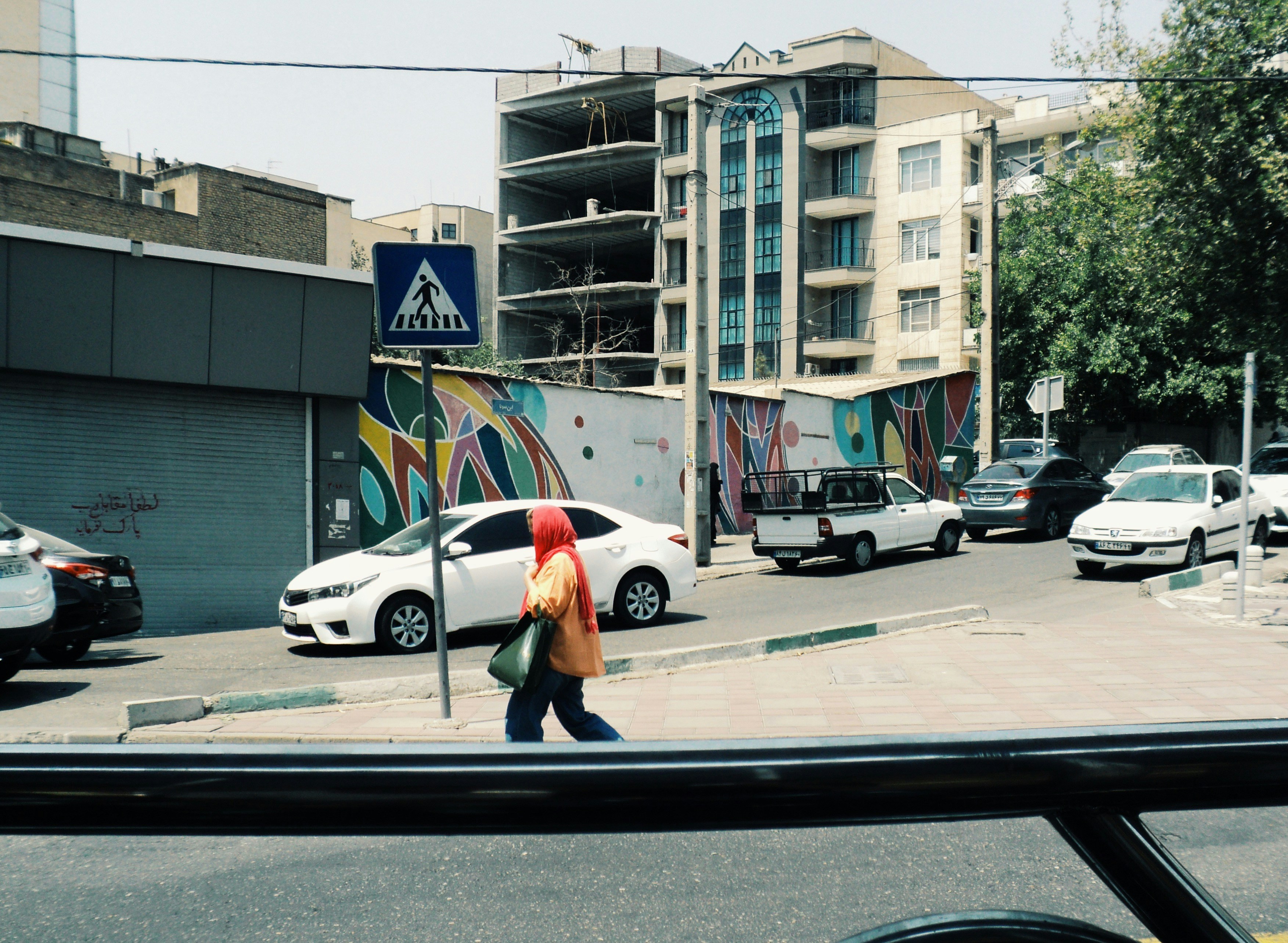 The beautiful, ordinary moments. | A woman crosses street, cars drive by.