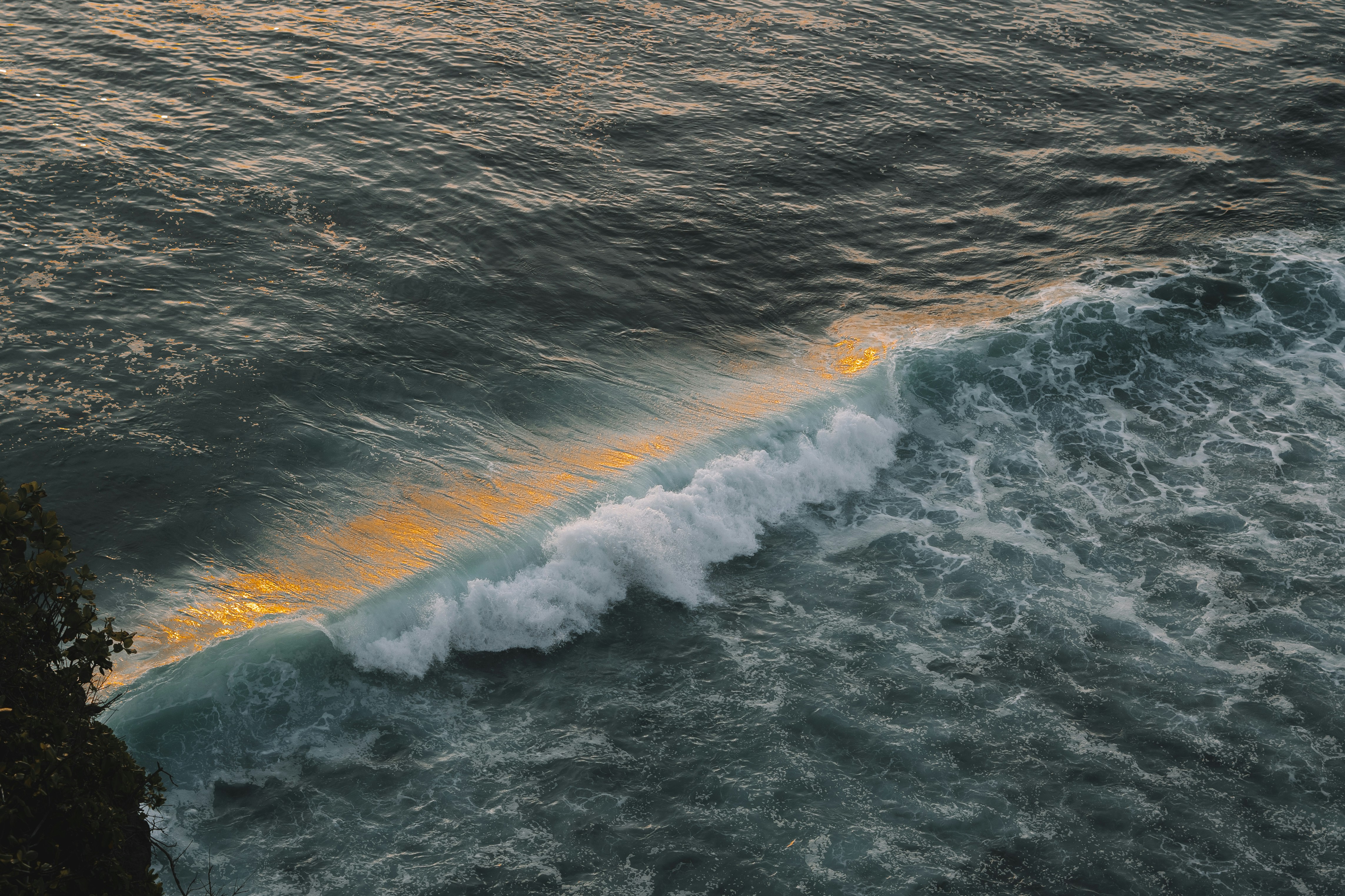 Gentle waves caress the shore, reflecting the warm hues of the setting sun. The scene captures the serene transition from day to night.