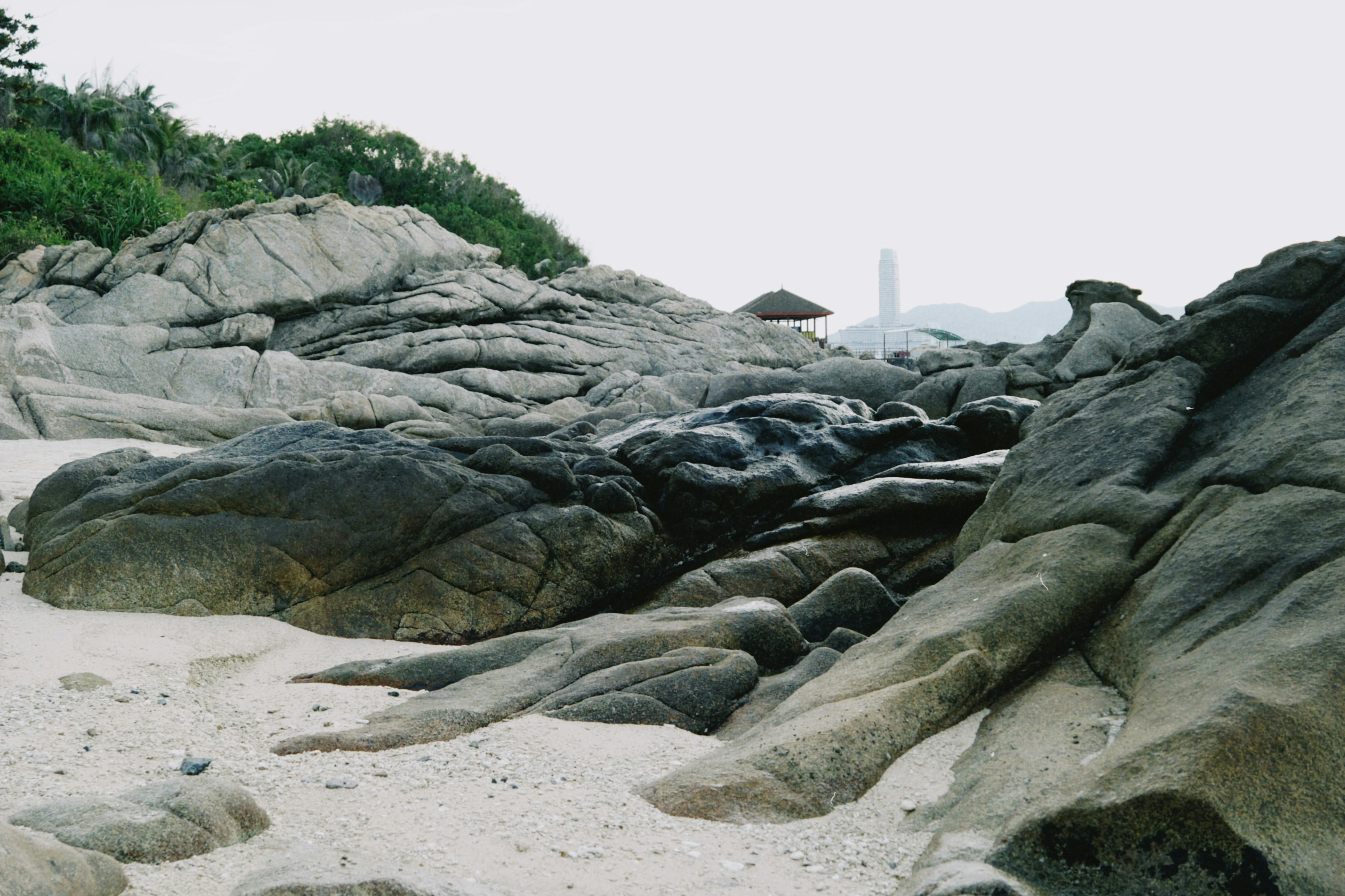 Rocky beach with large boulders and cloudy sky.