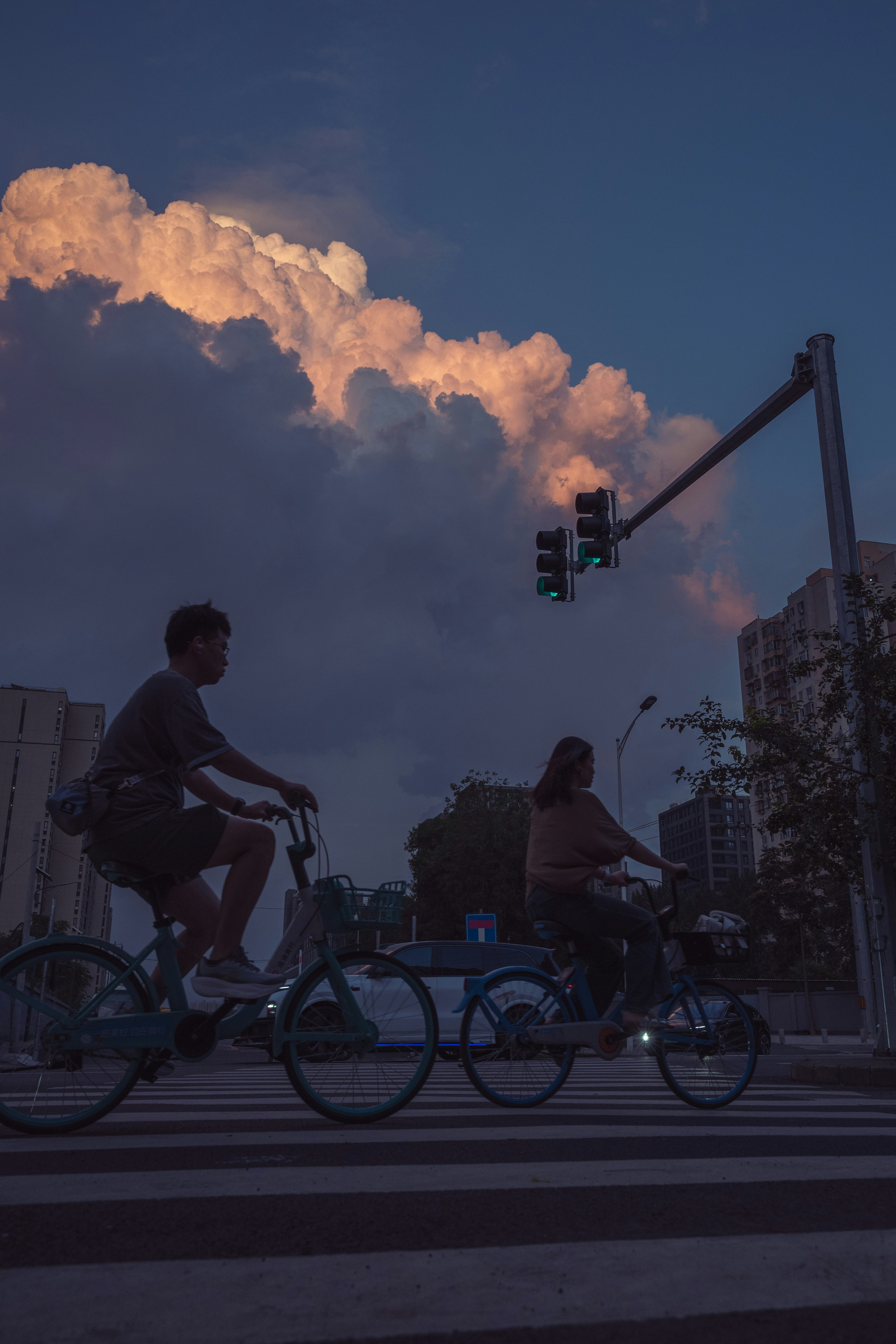 cumulonimbus | People bike under a dramatic, colorful cloud.