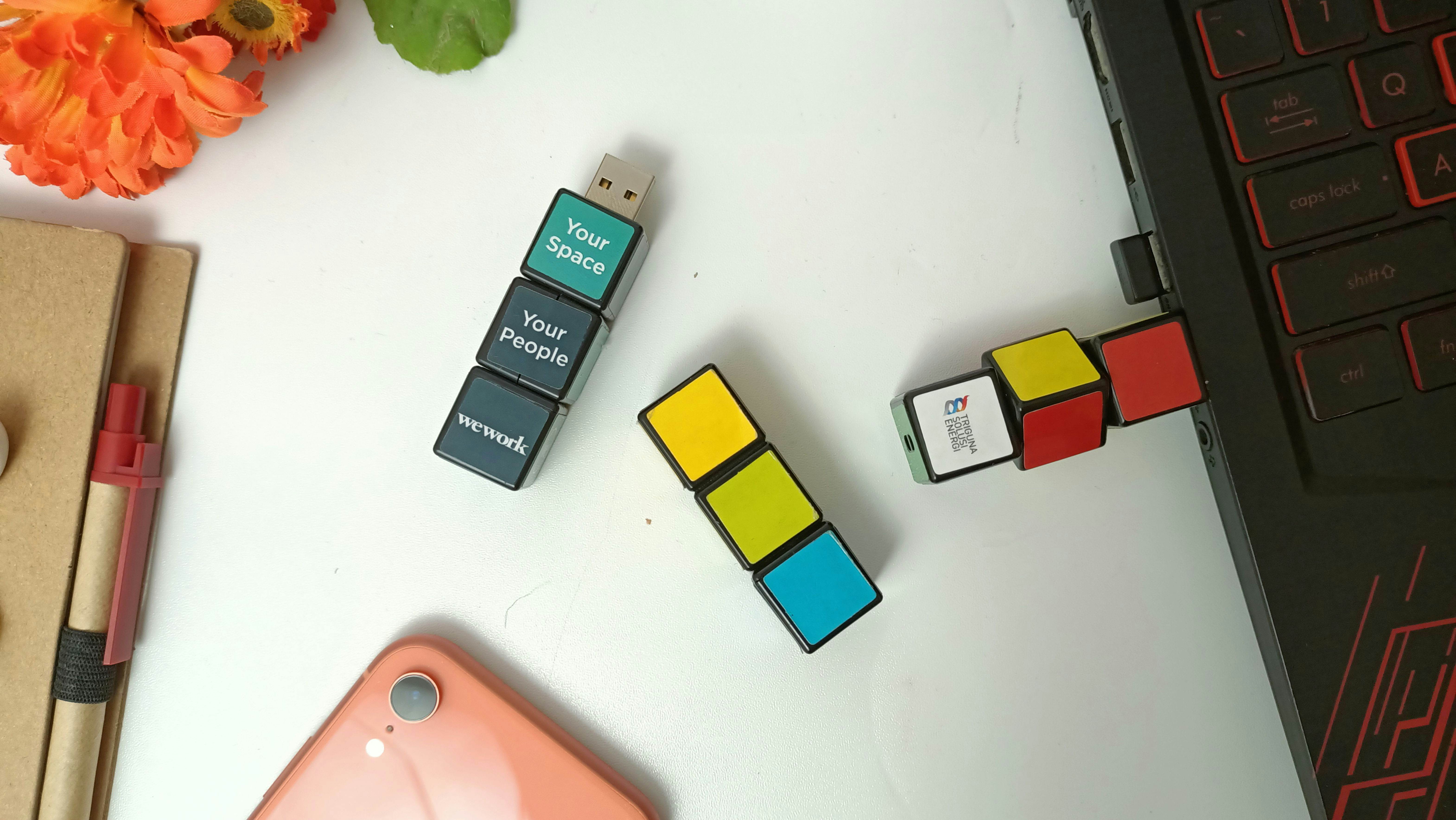 Souvenir Flashdisk Plastik - FDSPC25 | Flash drives in different colors lie on a desk.