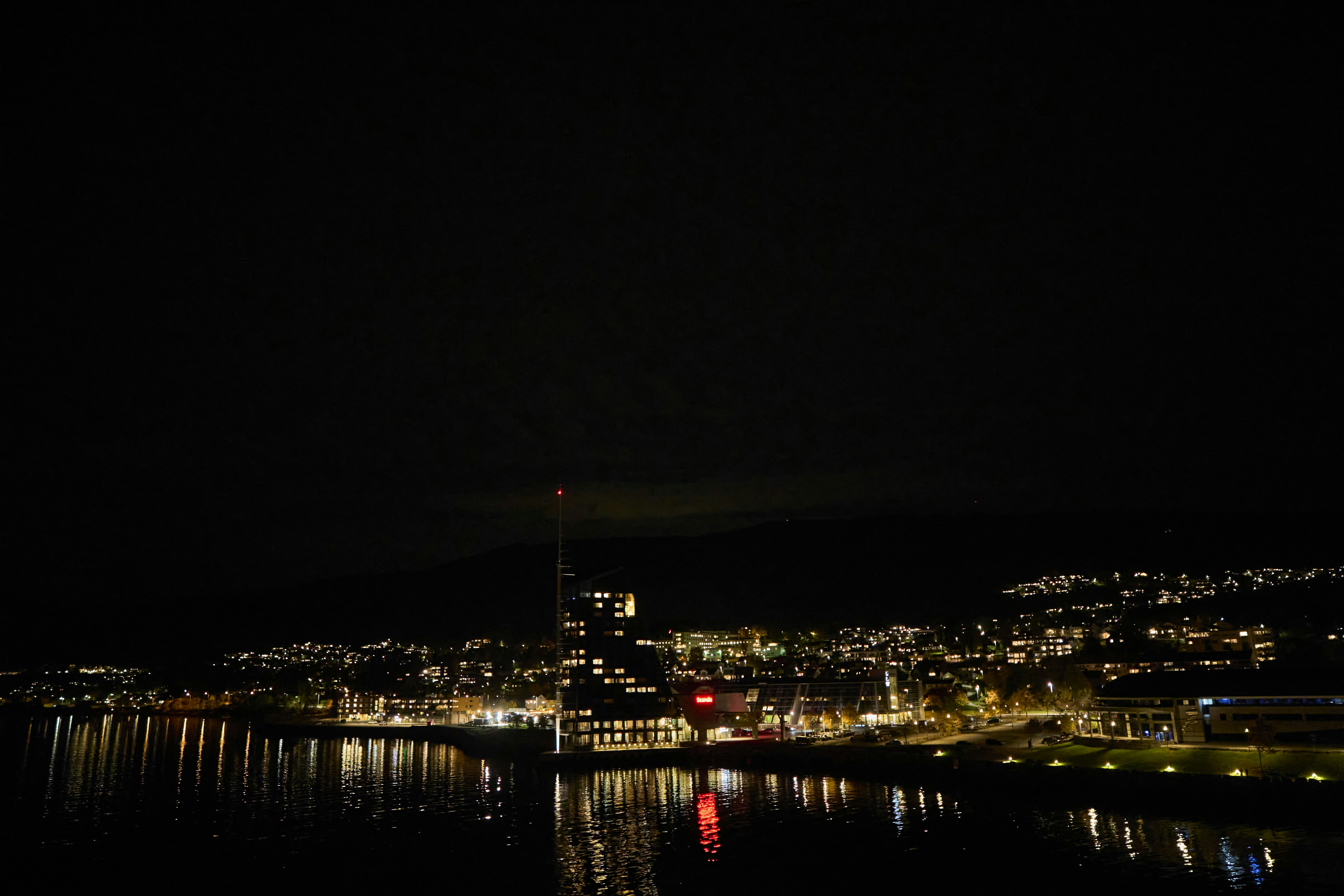City lights shine brightly along the dark waterfront.